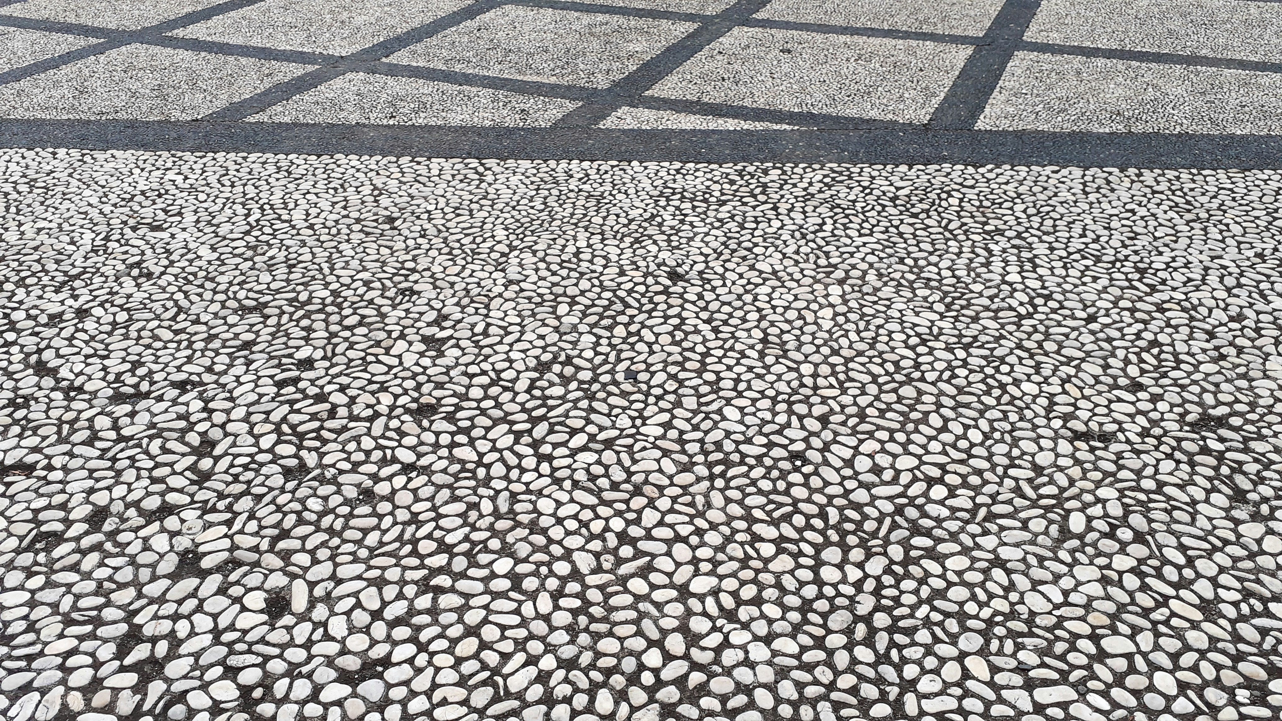 Close-up view of a pebble-strewn surface intersected by geometric patterns, showcasing unique textures and contrasts.