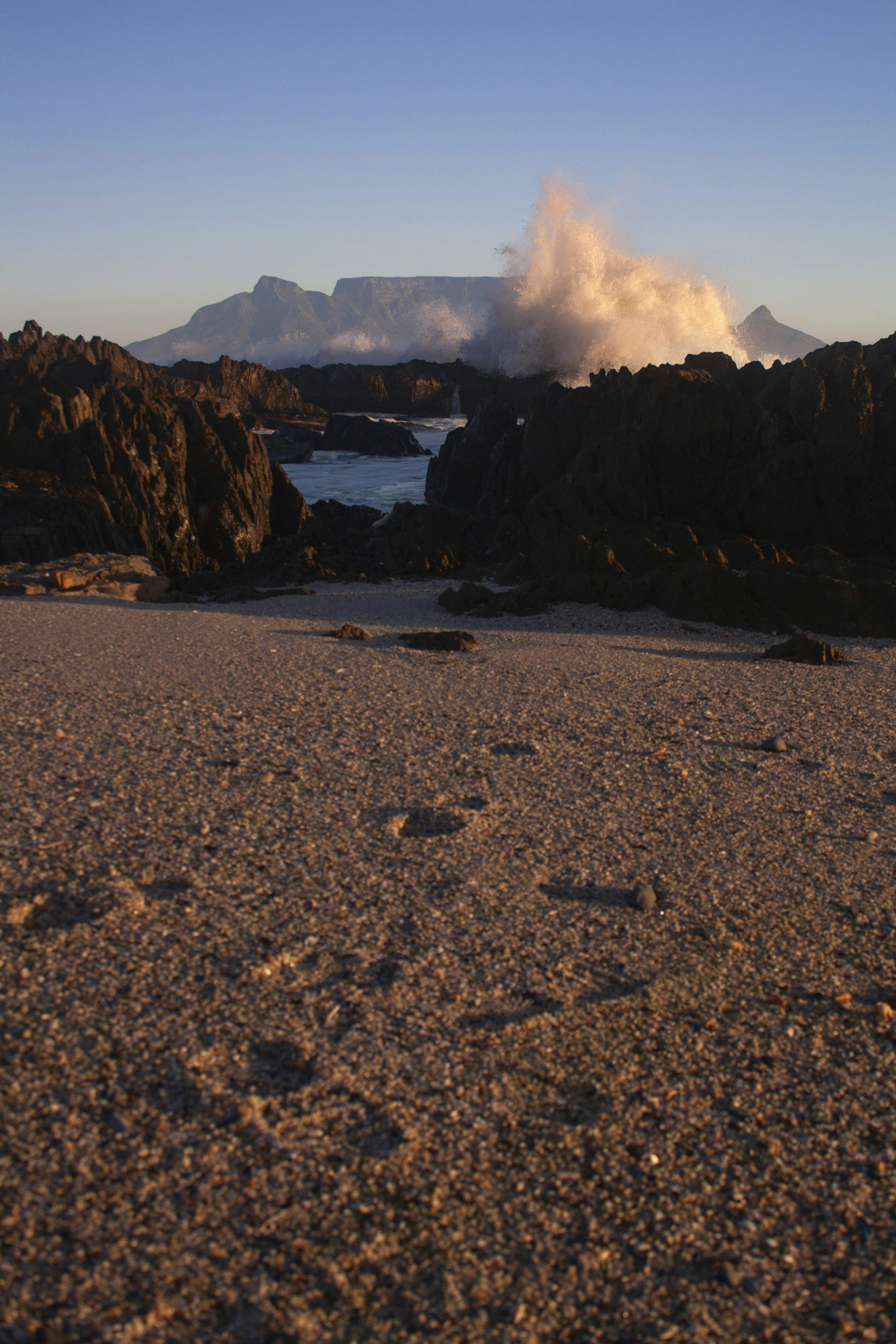Dusk Plume Over Basalt: Sea Spray Erupts Against Jagged Coast