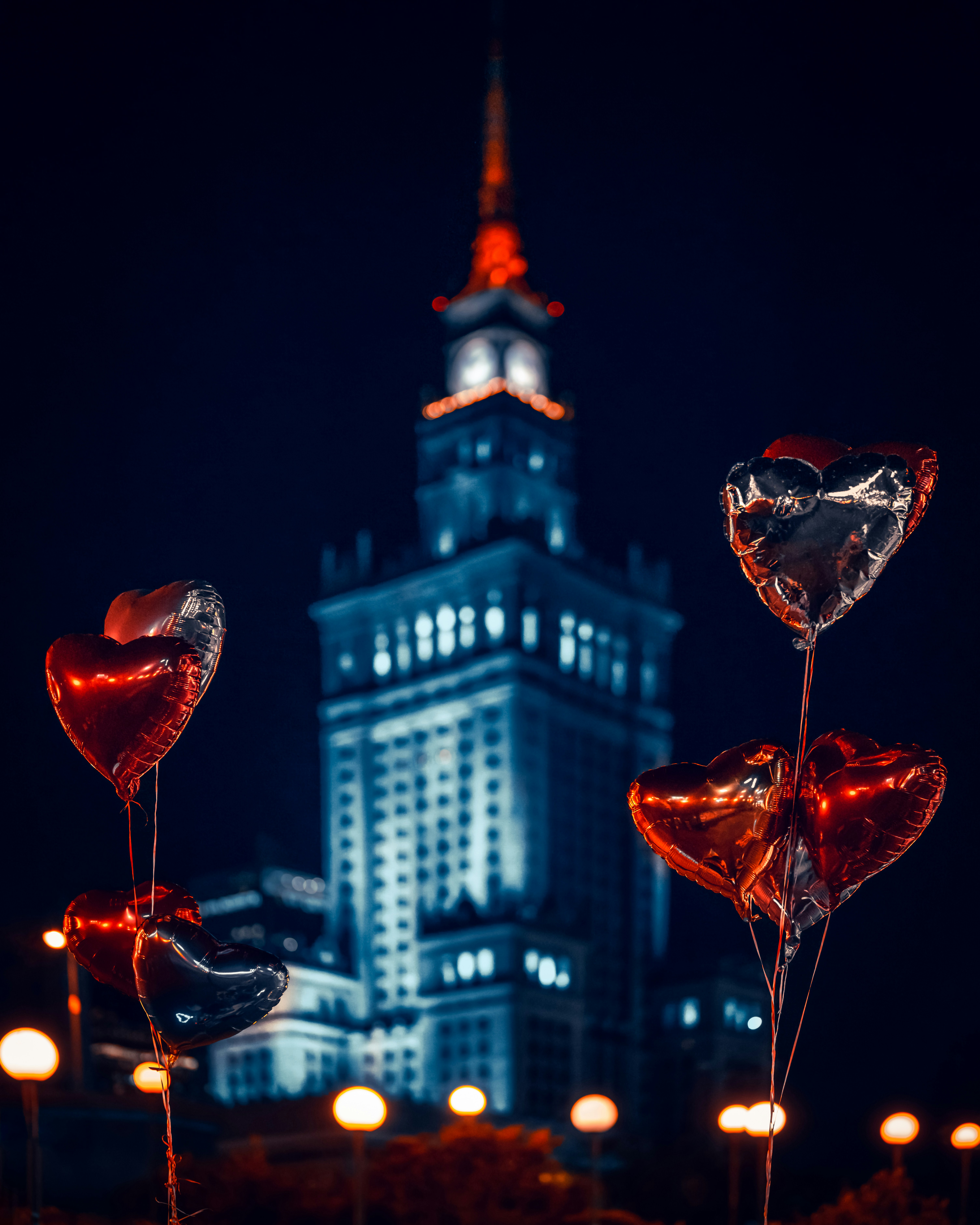 Blue-Spire Nightscape Framed by Floating Red Heart Balloons