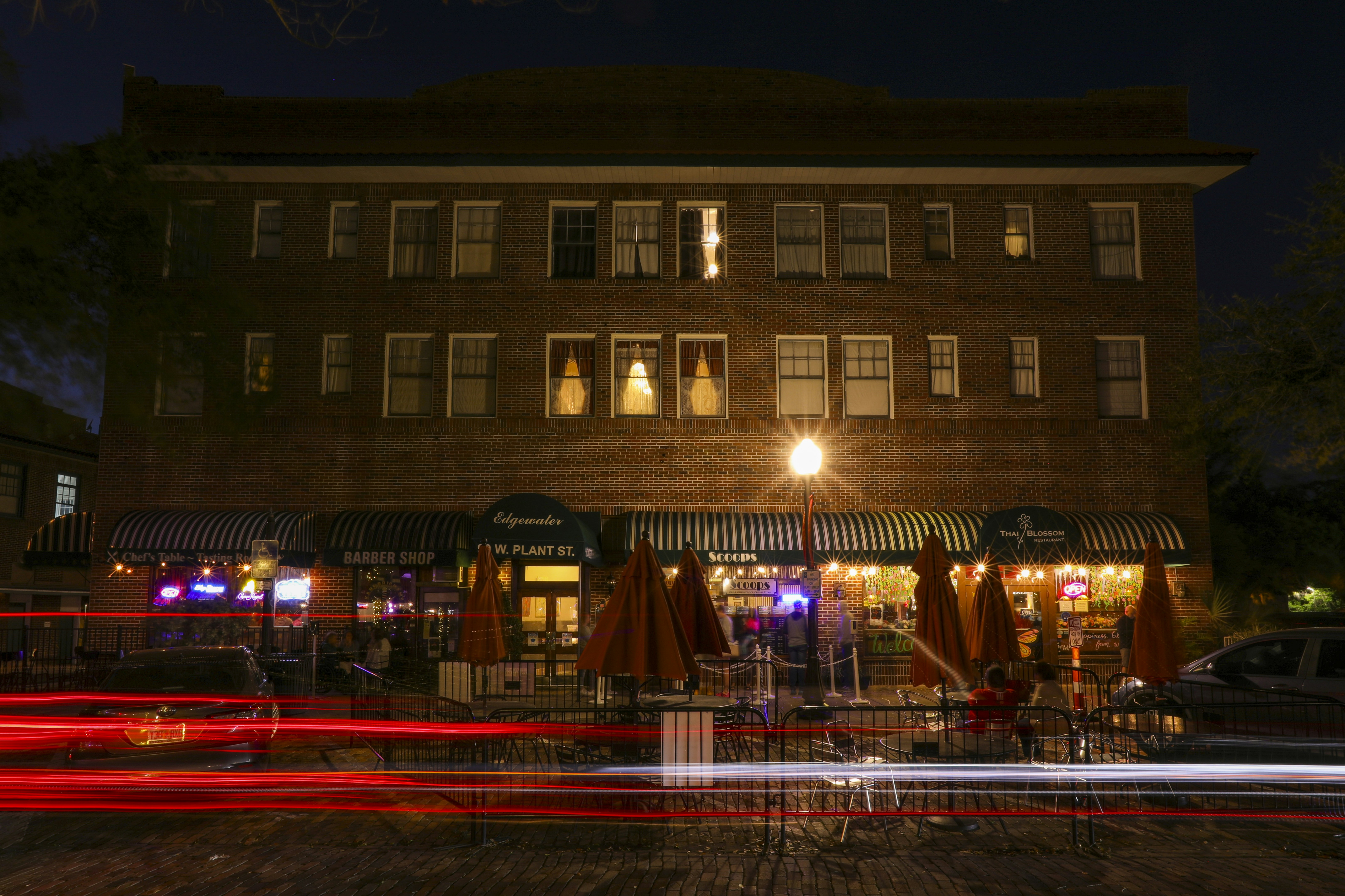 Historic brick building illuminated at night with motion blur from passing car lights.