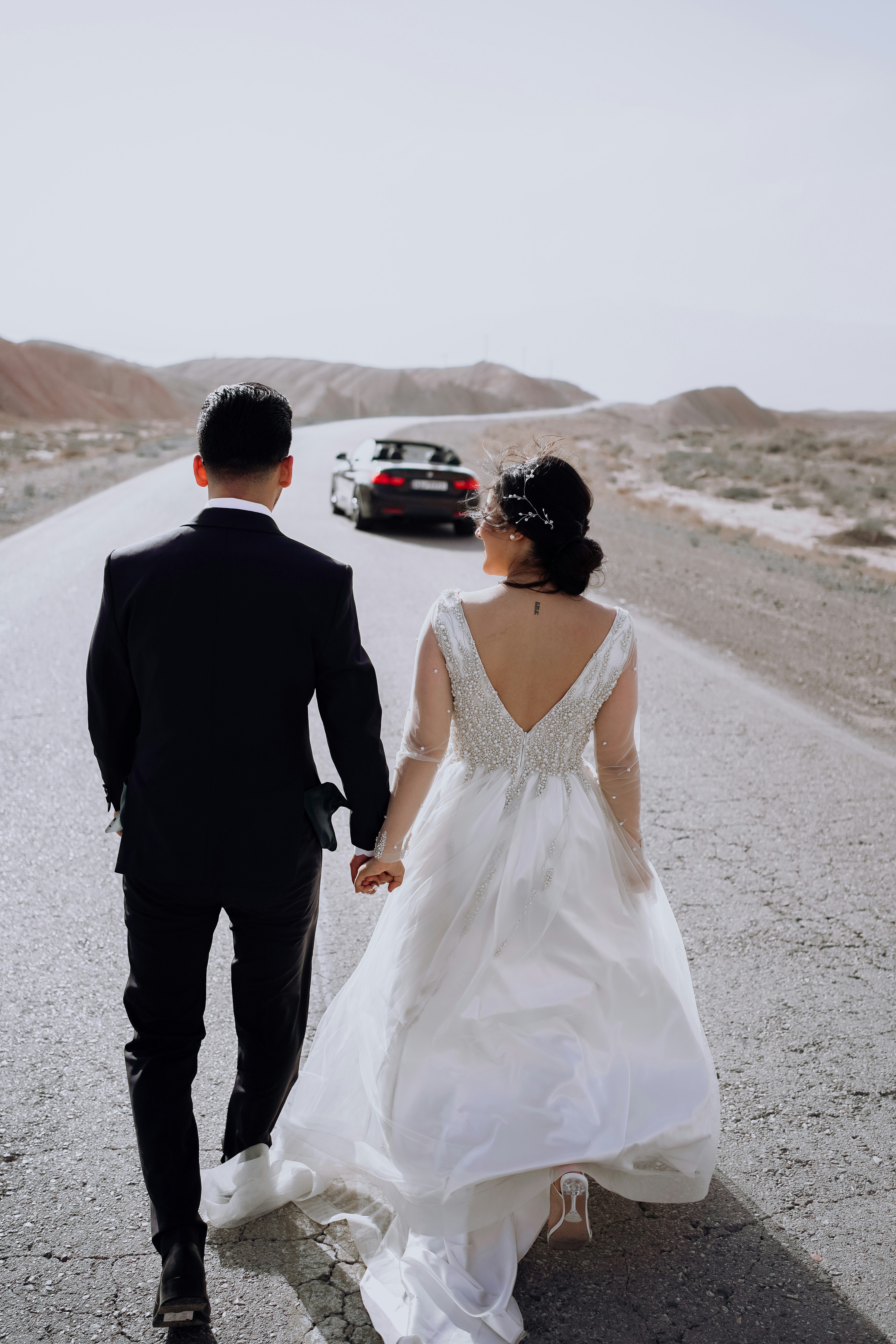 A bride and groom walking down the road holding hands photo – Free ...