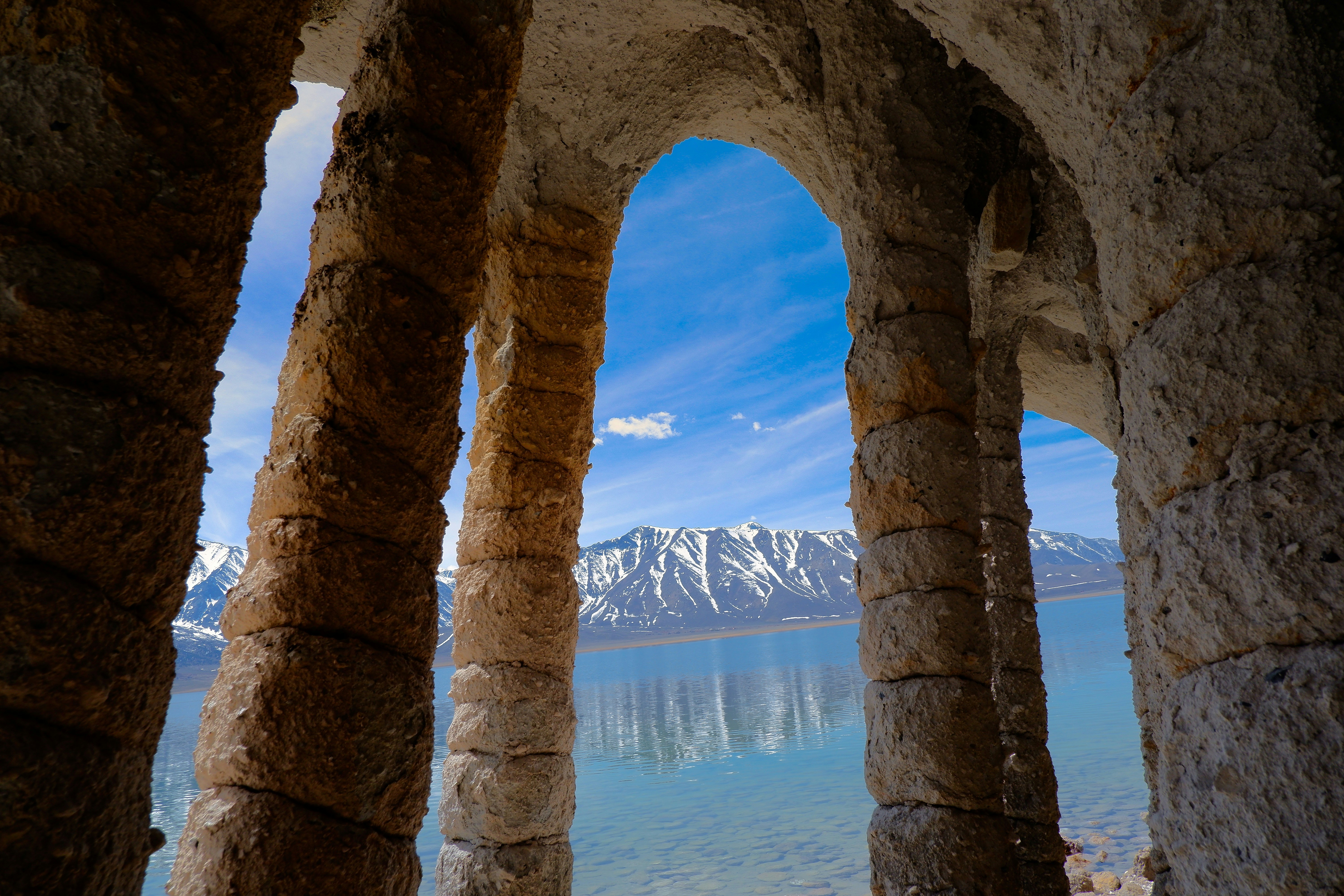 A view of a lake through some stone arches photo – Free California ...