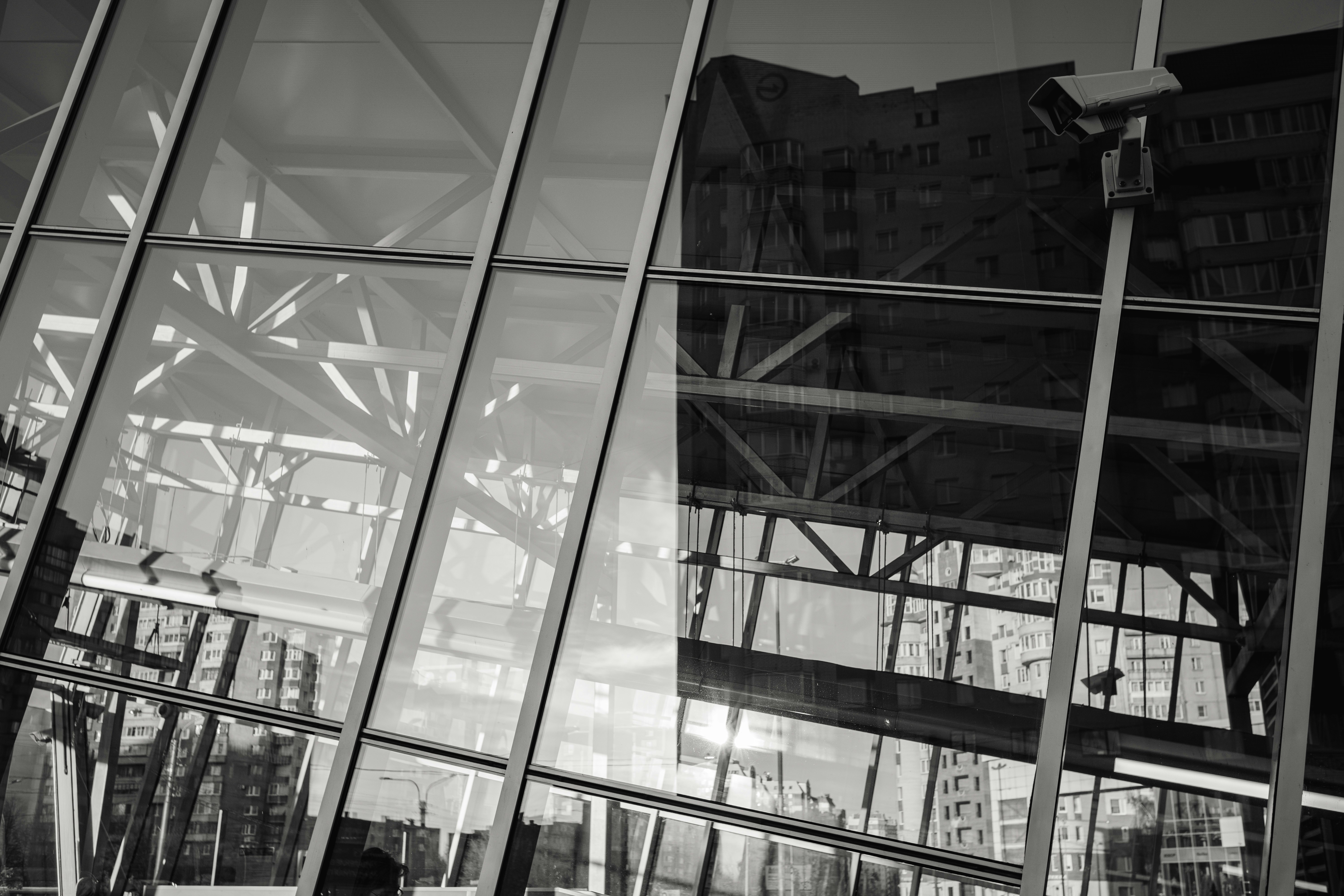 Geometric patterns and reflections merge in a striking interplay of light and shadow on a glass facade, showcasing urban architecture.