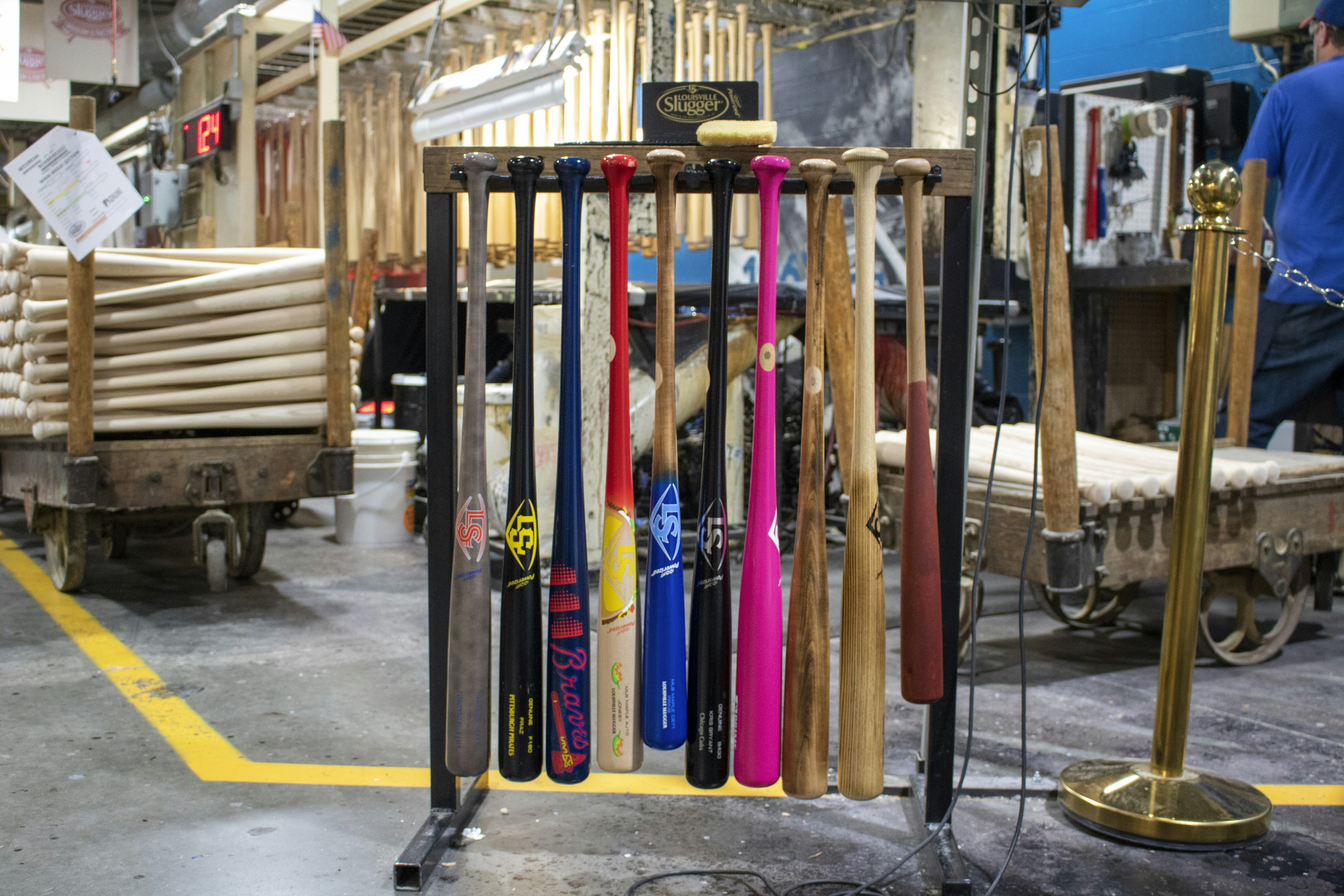 Rack of various baseball bats displayed in an industrial warehouse setting.