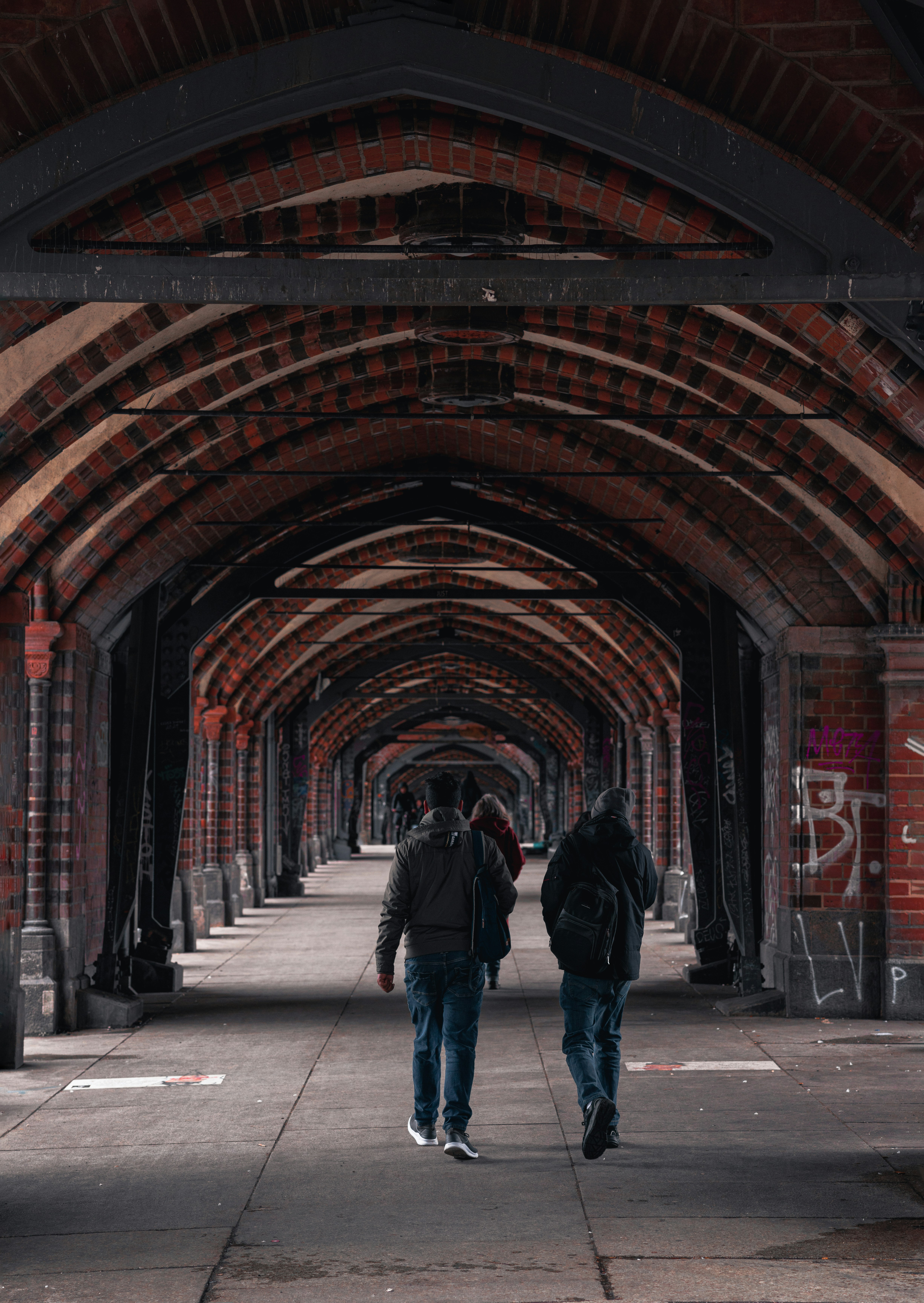 Two Wanderers in a Receding Brick Arcade