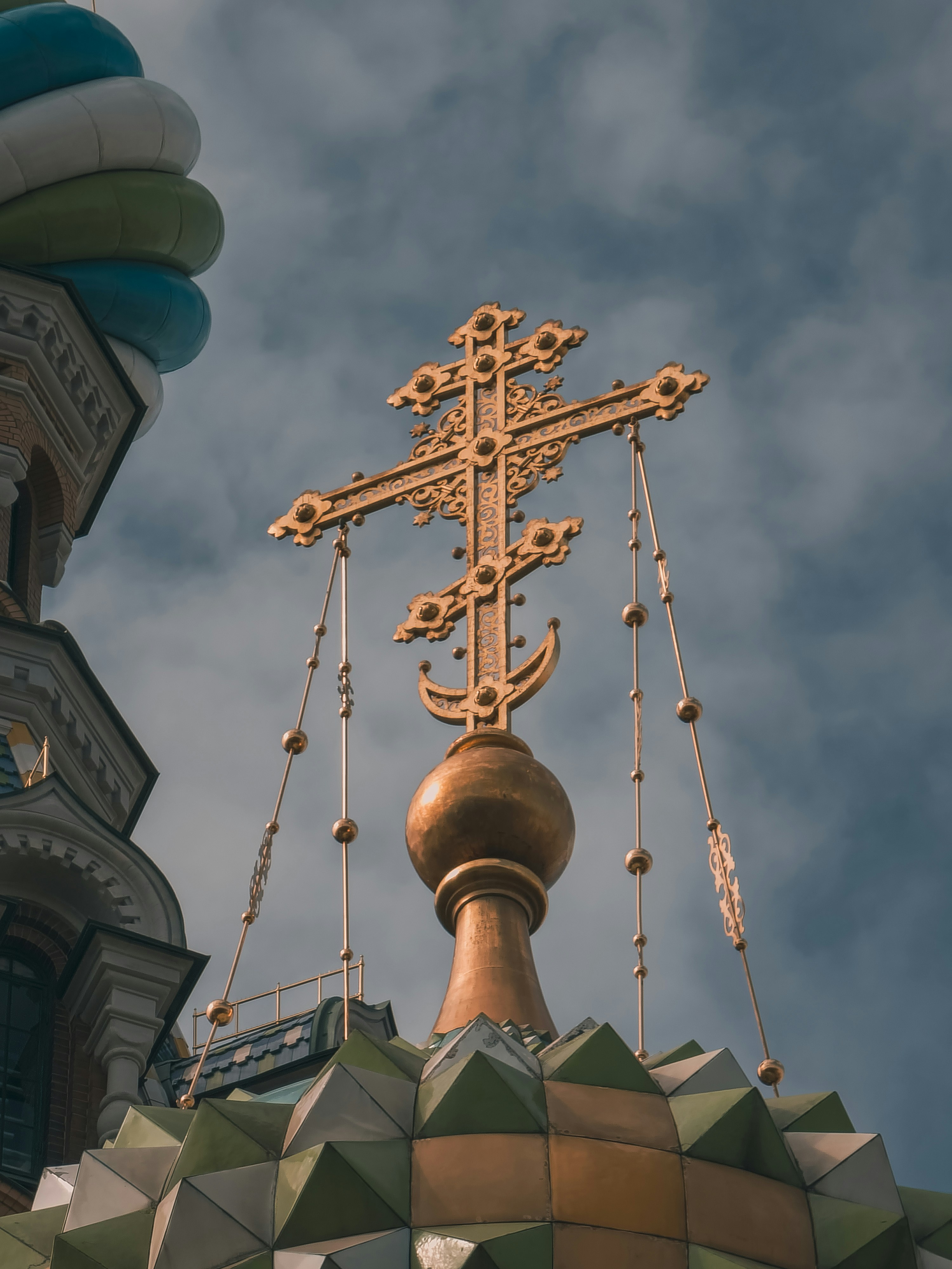 Golden Cross Above a Geometric Cathedral Roof Under a Quiet Sky