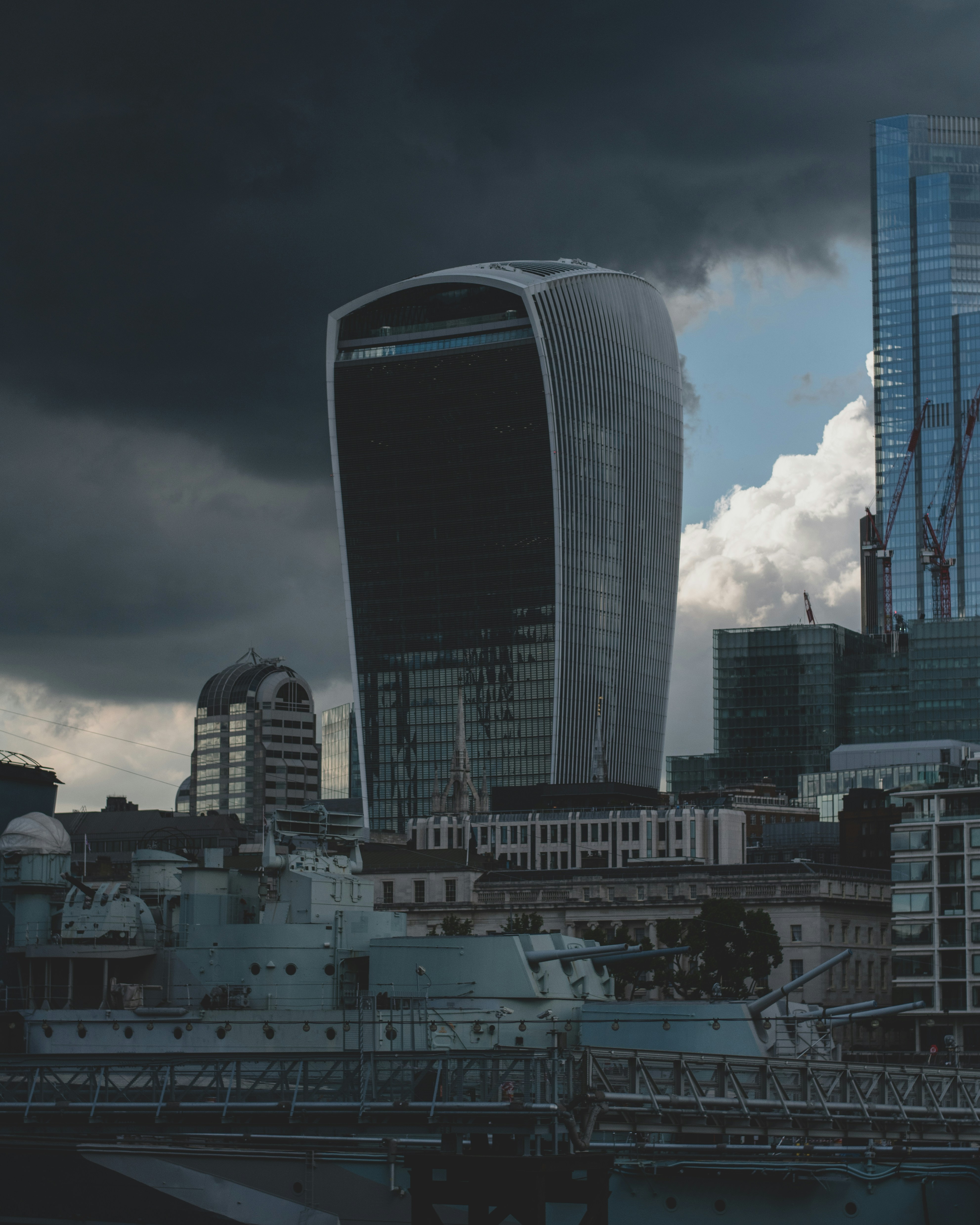 Modern skyscrapers rise against a dramatic sky, showcasing the contrast between architectural innovation and nature's power.
