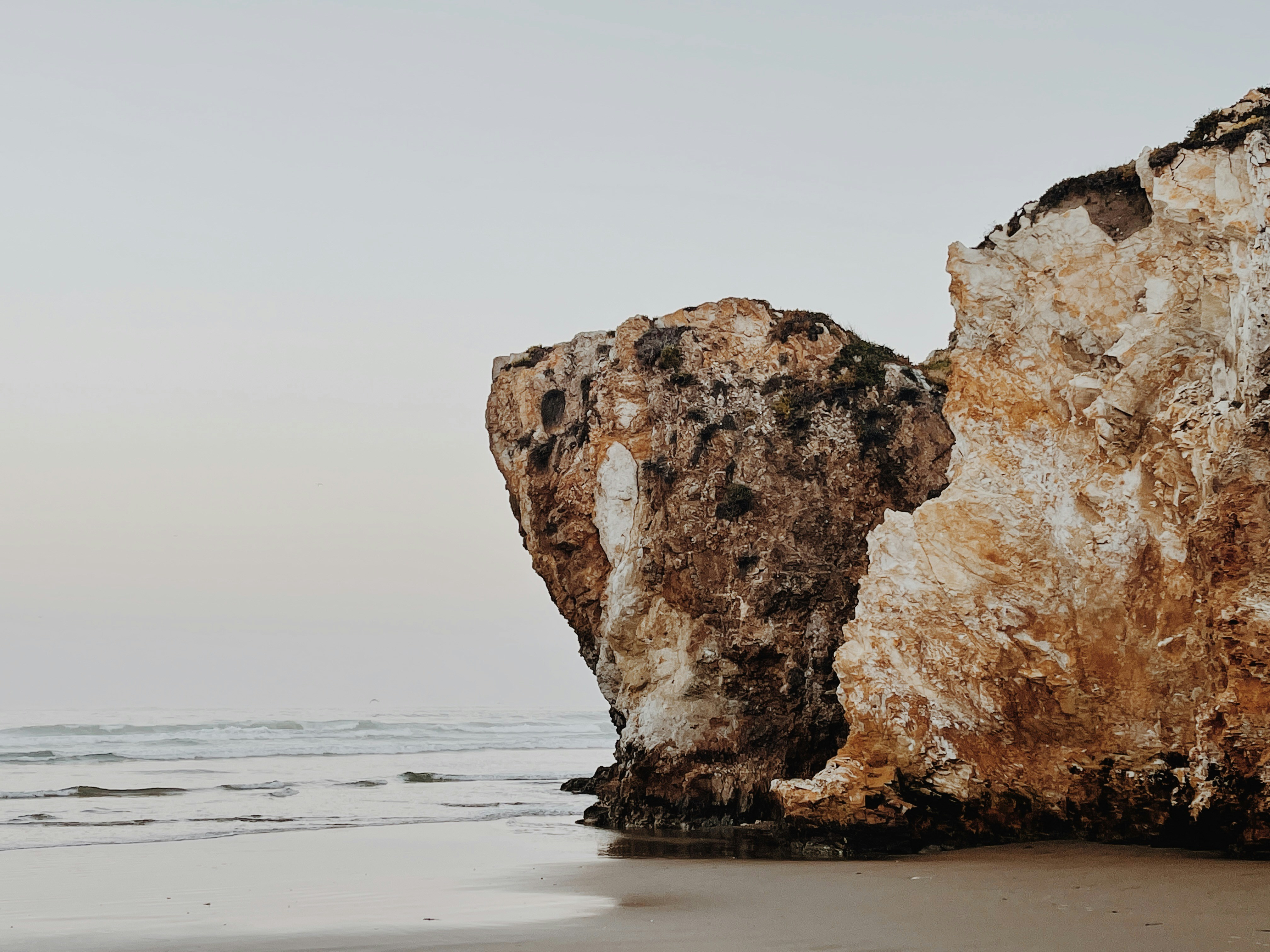 Un gros rocher assis au sommet d’une plage de sable photo – Image ...