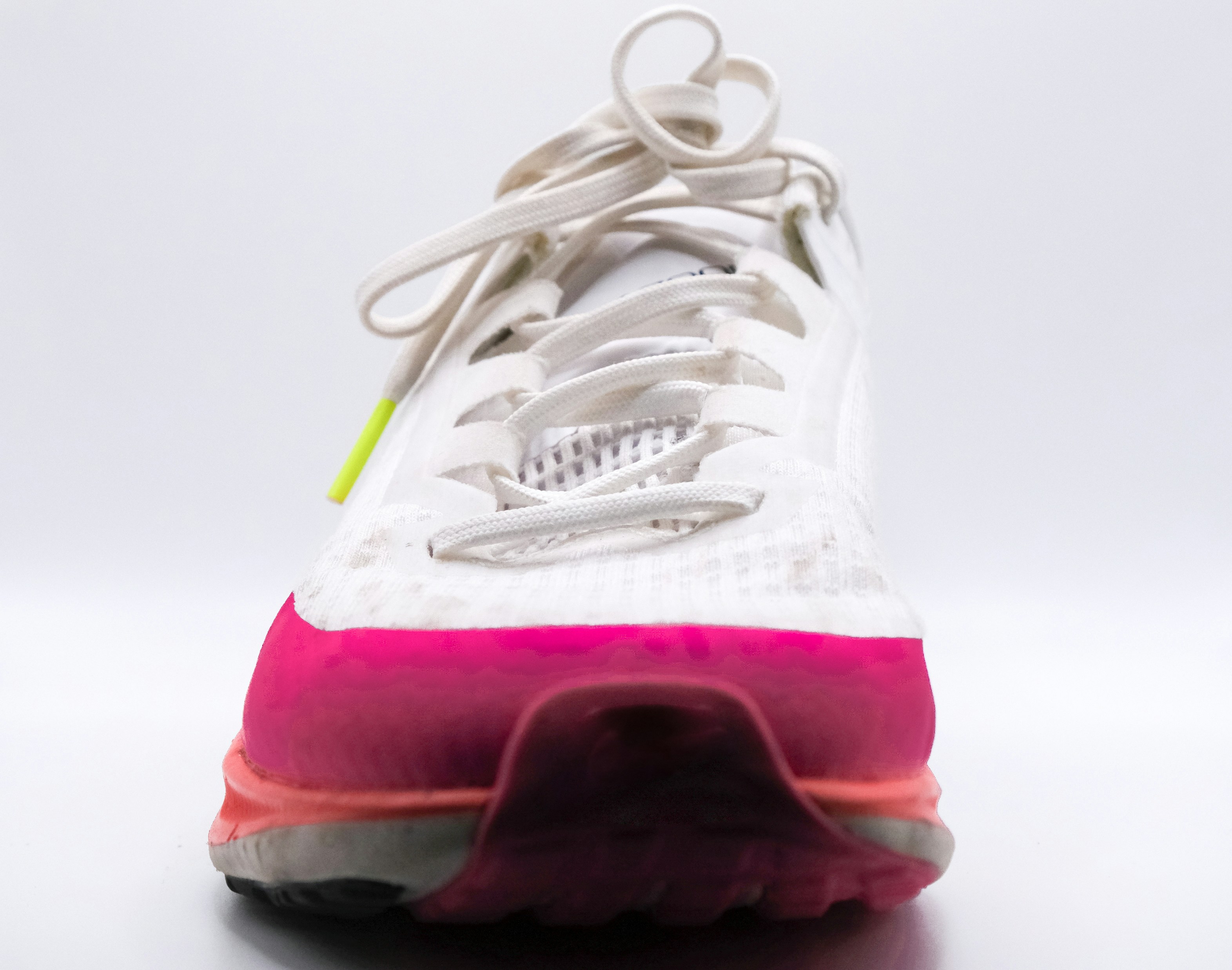 Front-row focus: white running shoe with neon accent and pink toe