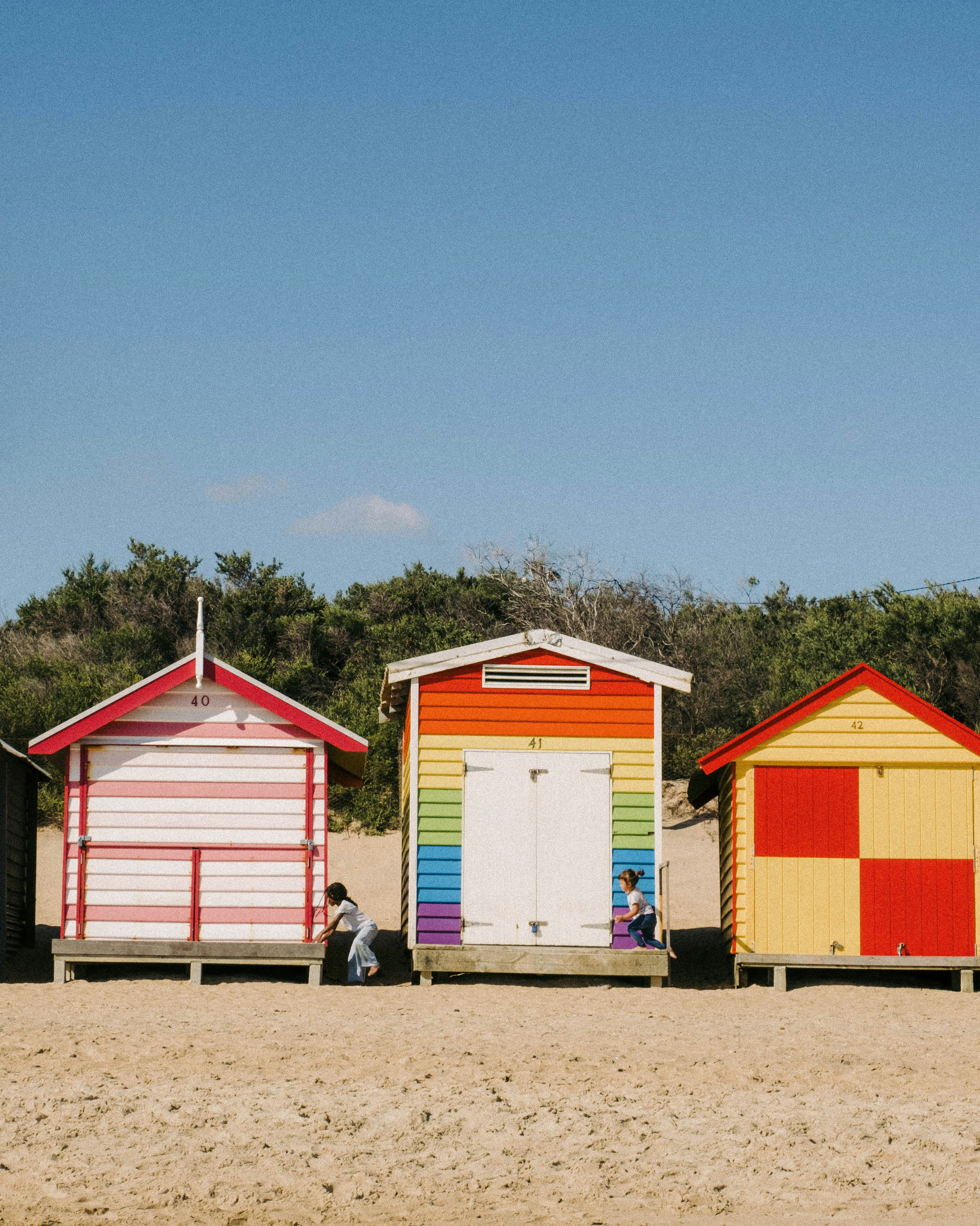 Three Colorful Beach Cabins Stand Guard Over Sandy Shore