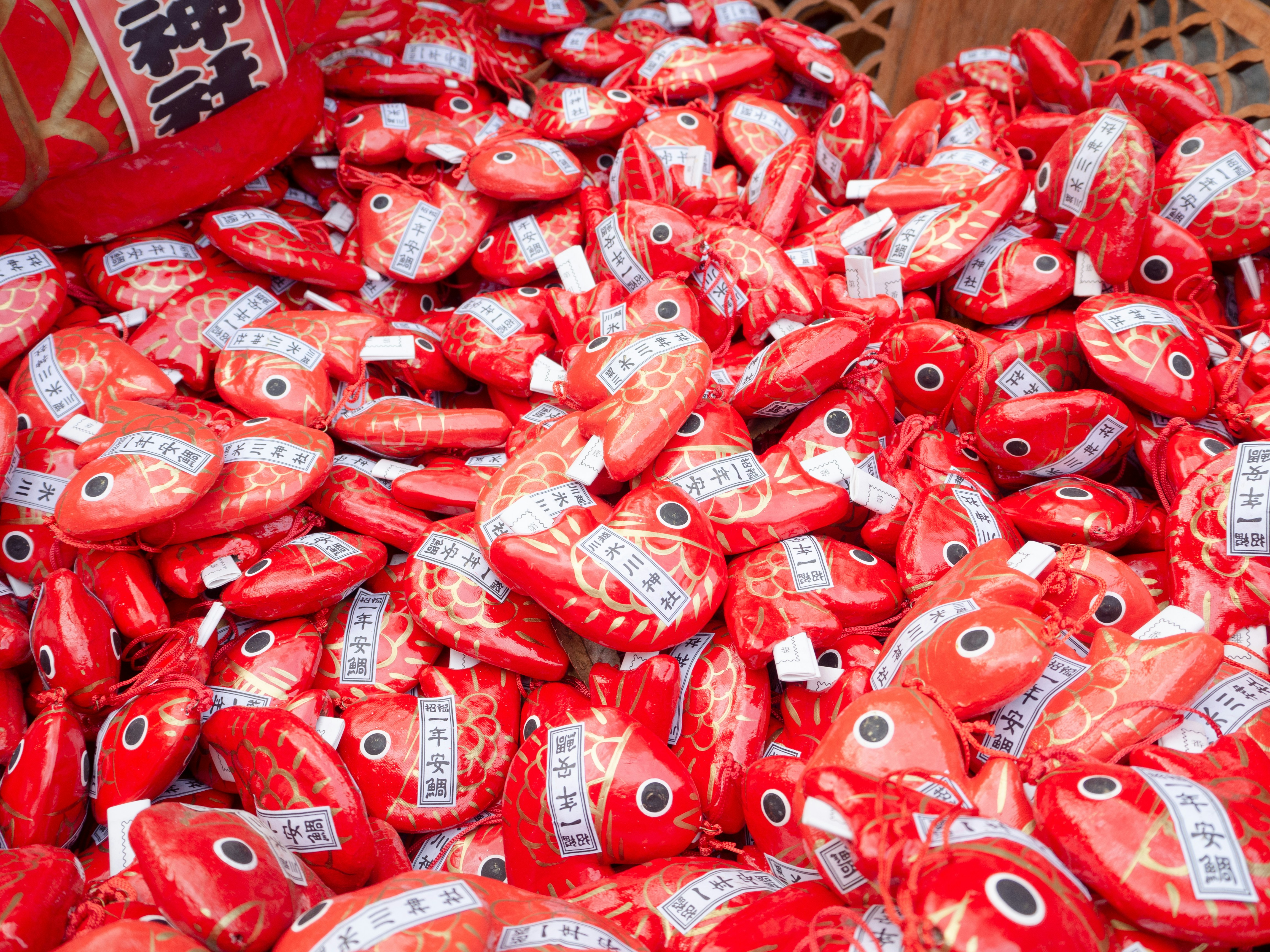 Red fish-shaped charms with white inscriptions piled together, symbolizing luck and prosperity.