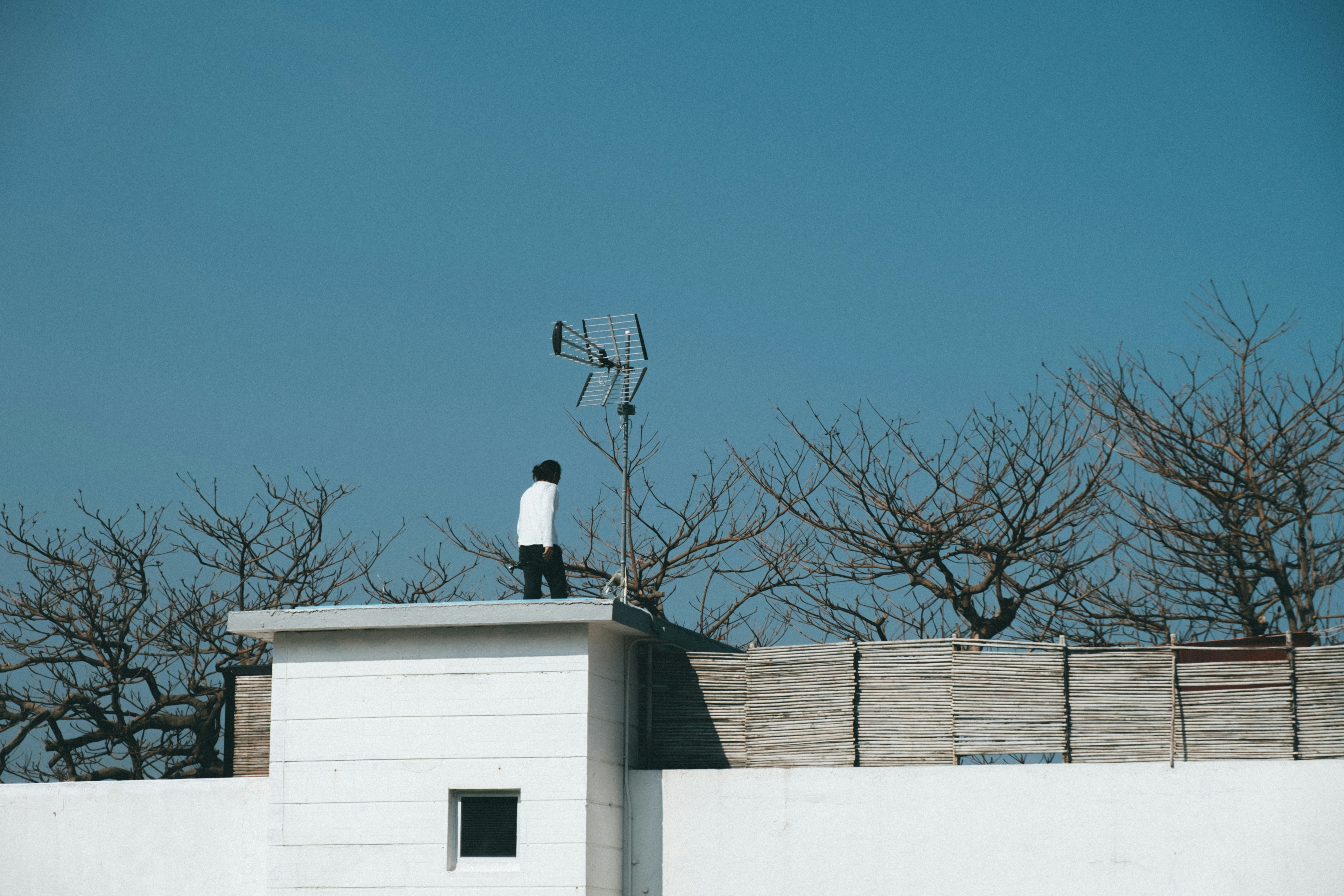 a man standing on top of a roof next to a wind vane