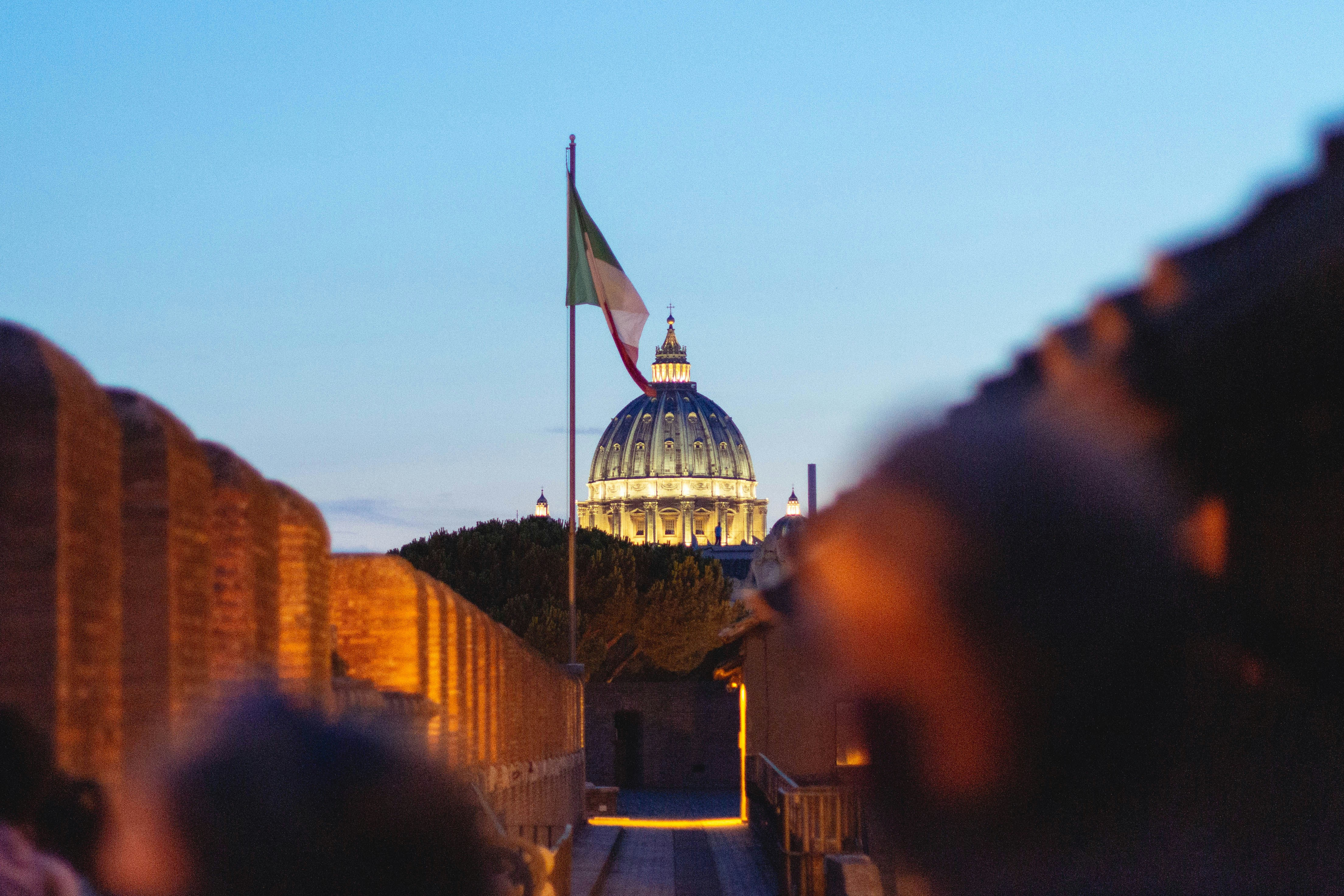 Silhouette of St. Peter's Basilica dome framed by Castel Sant'Angelo's walls at dusk.