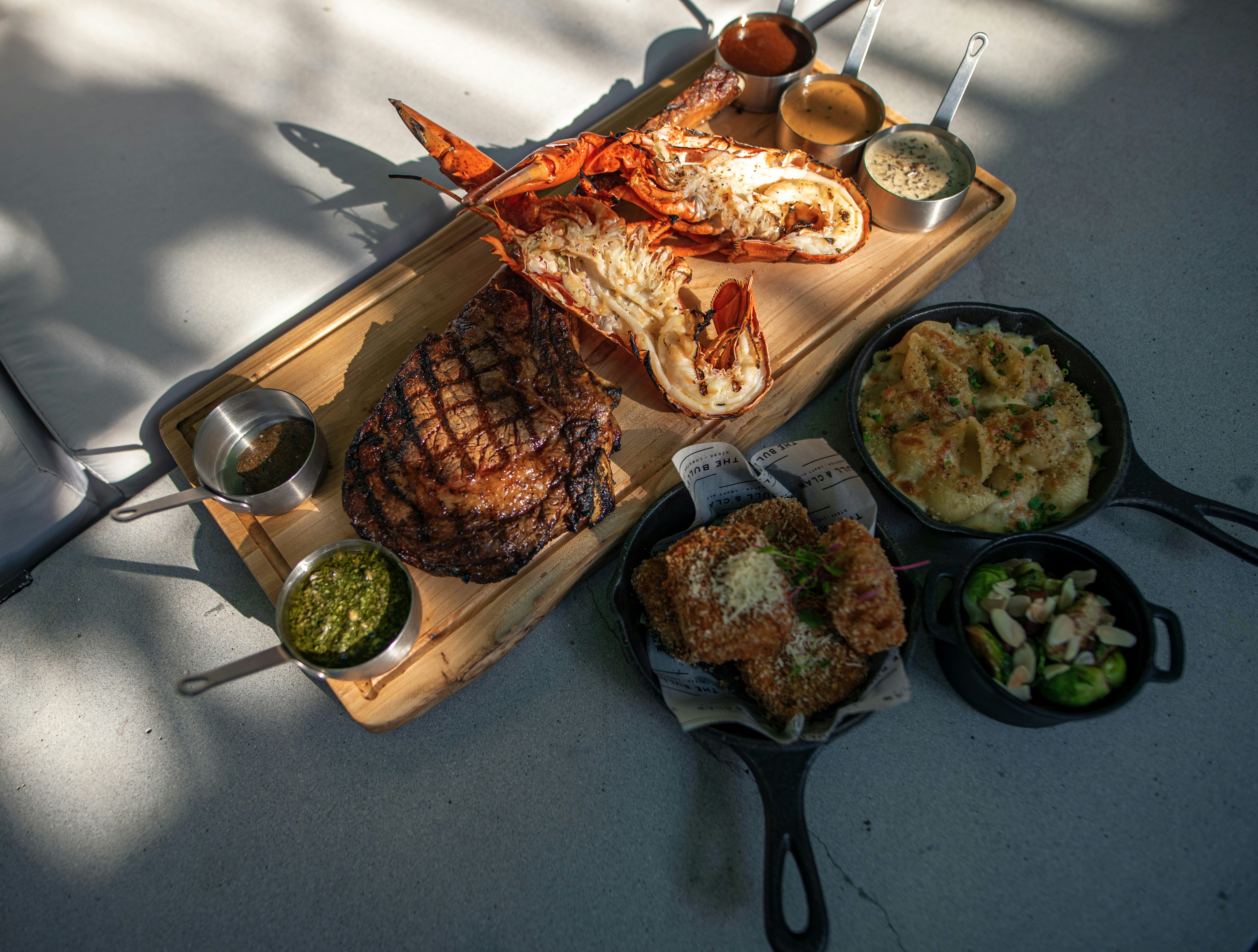 Coastal Surf and Sizzle: Lobster, Steak, and Crispy Bites on a Wooden Board