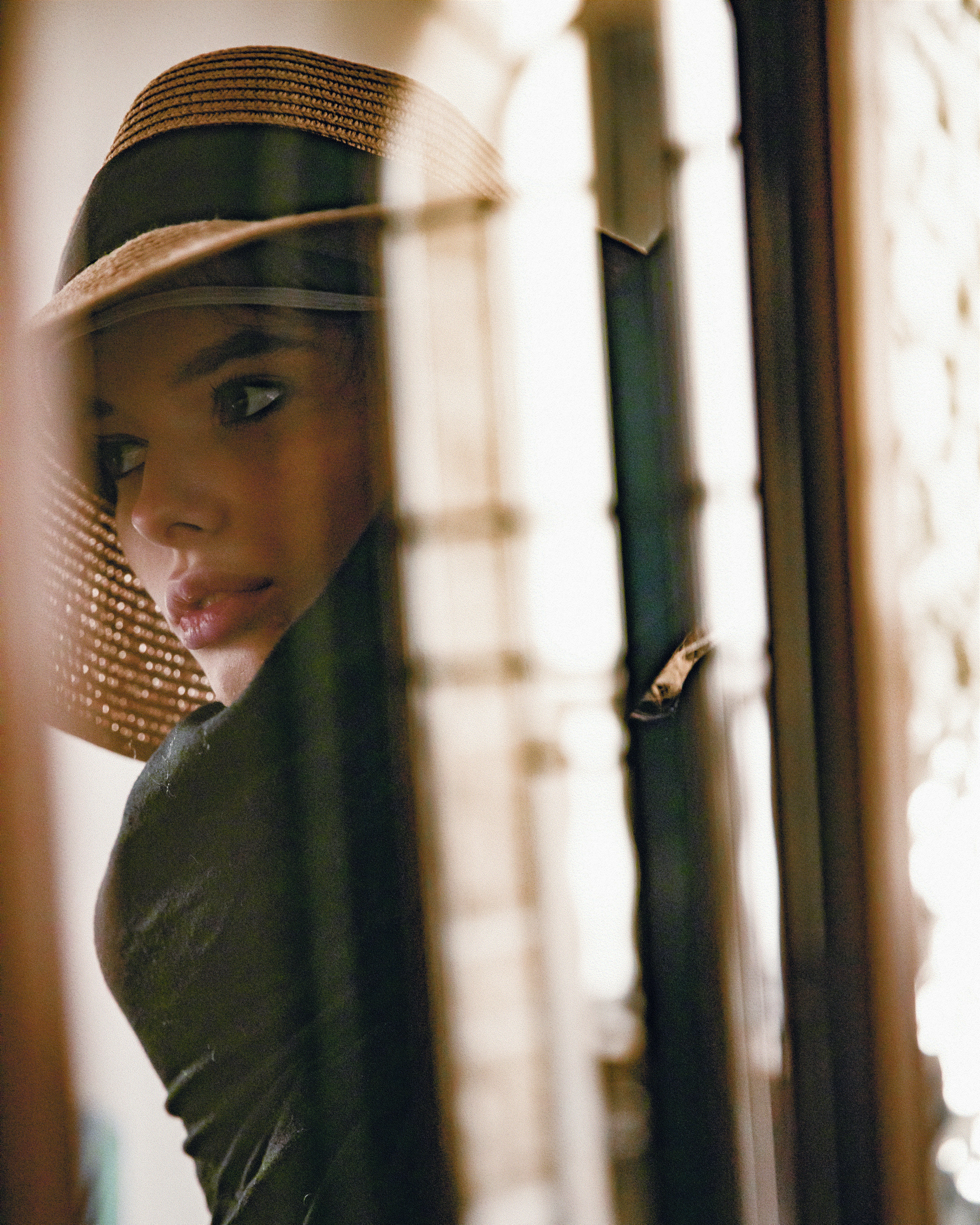 A woman wearing a hat looking out a window photo – Free Clothing Image ...