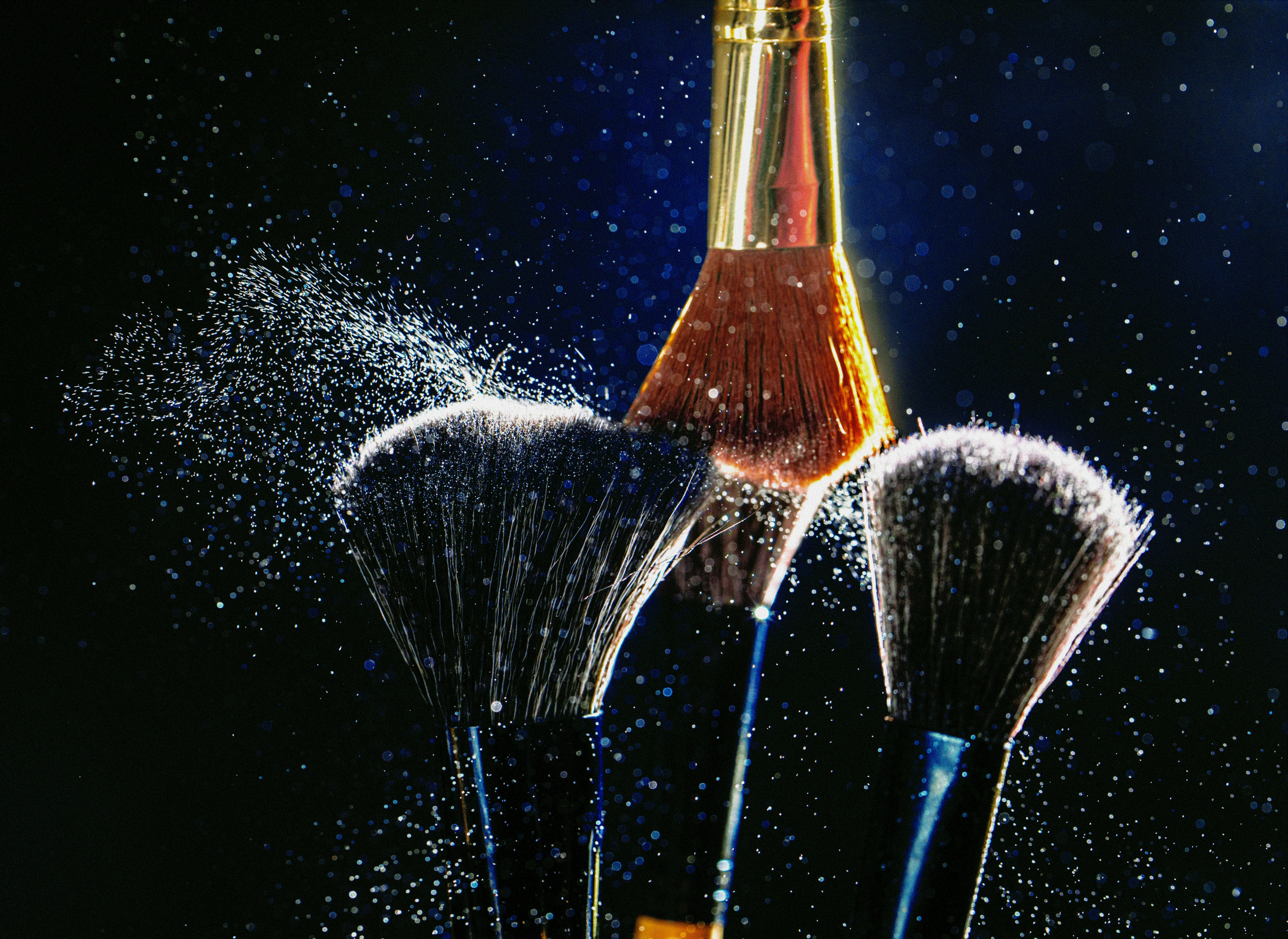 a close up of three brushes with water splashing on them