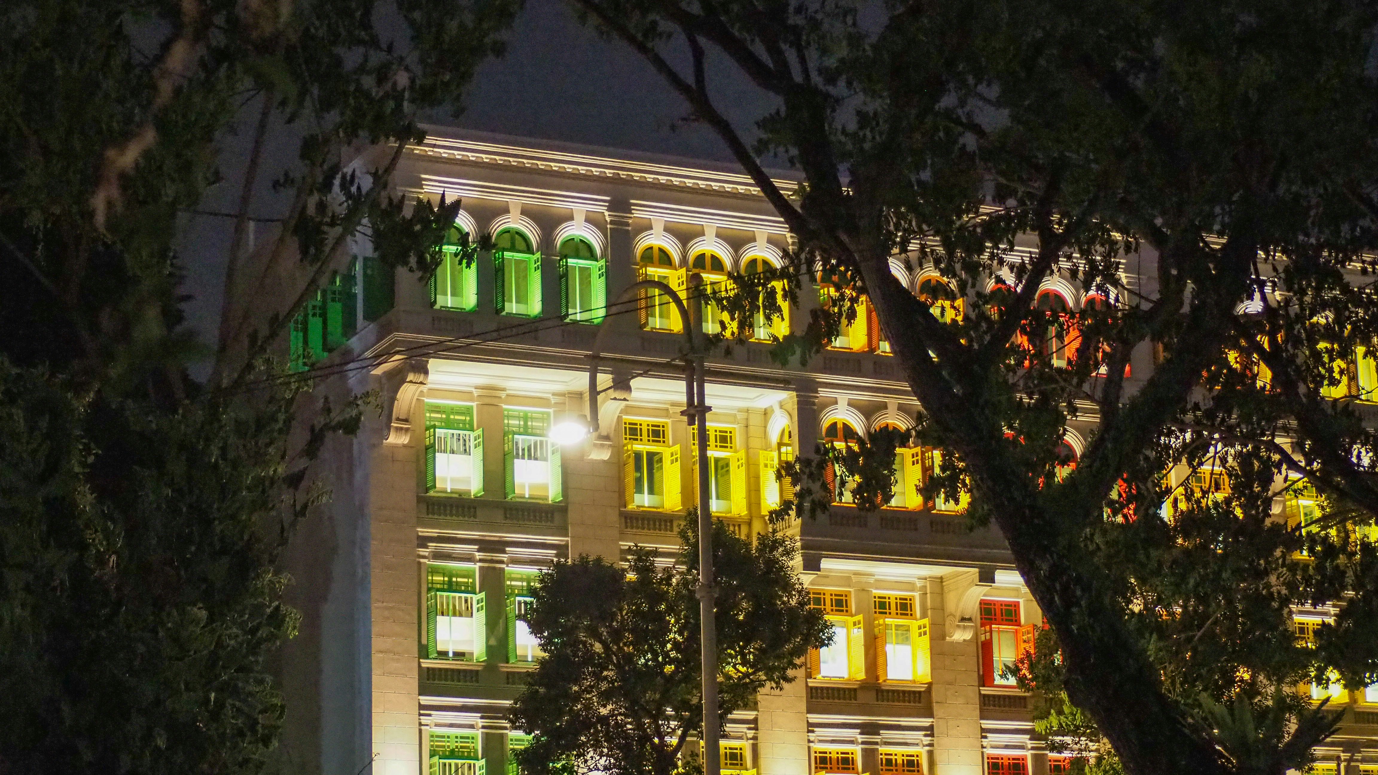 A tall building with many windows lit up at night photo – Free Building ...