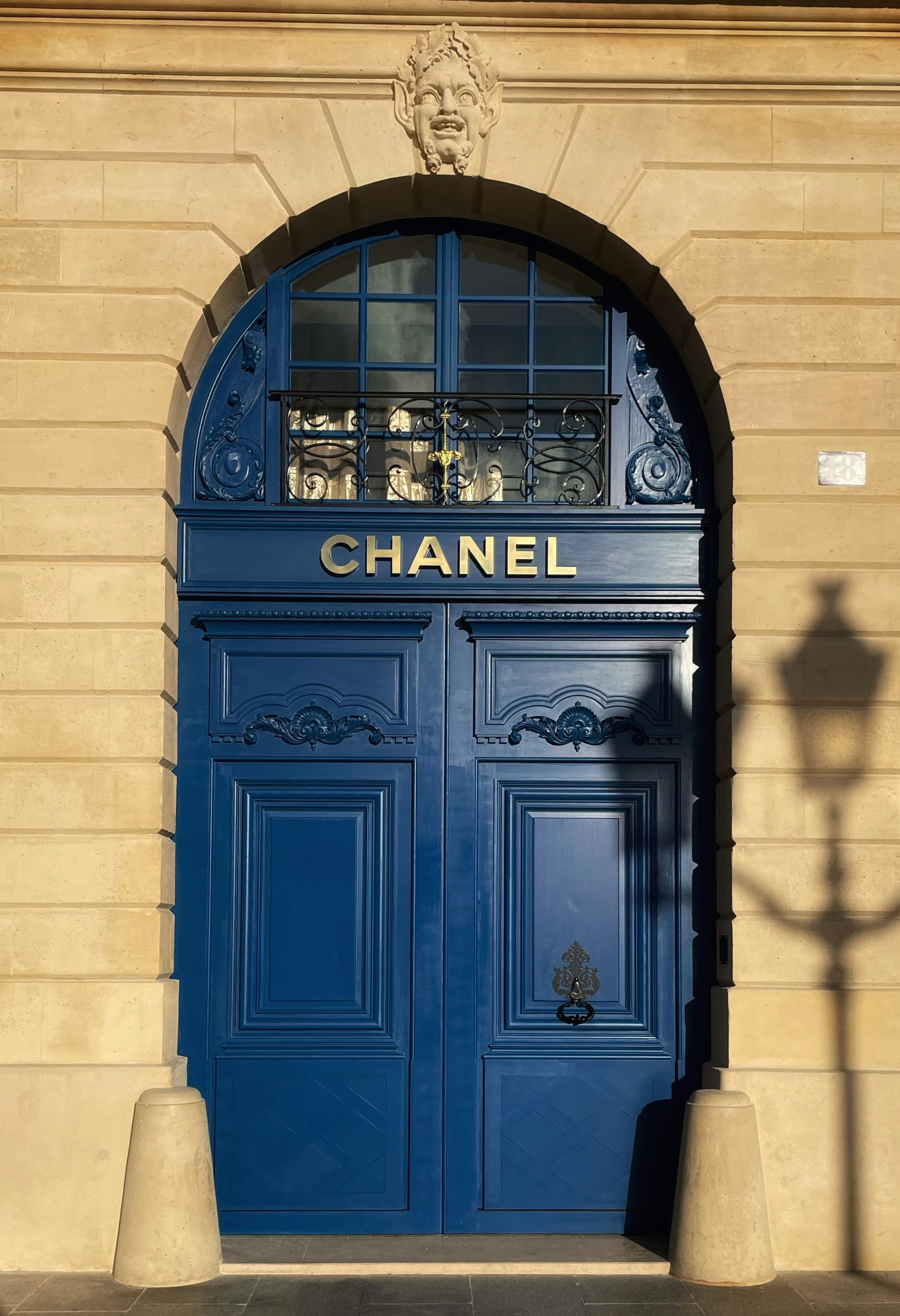 Blue door with Chanel sign at a sunlit stone facade