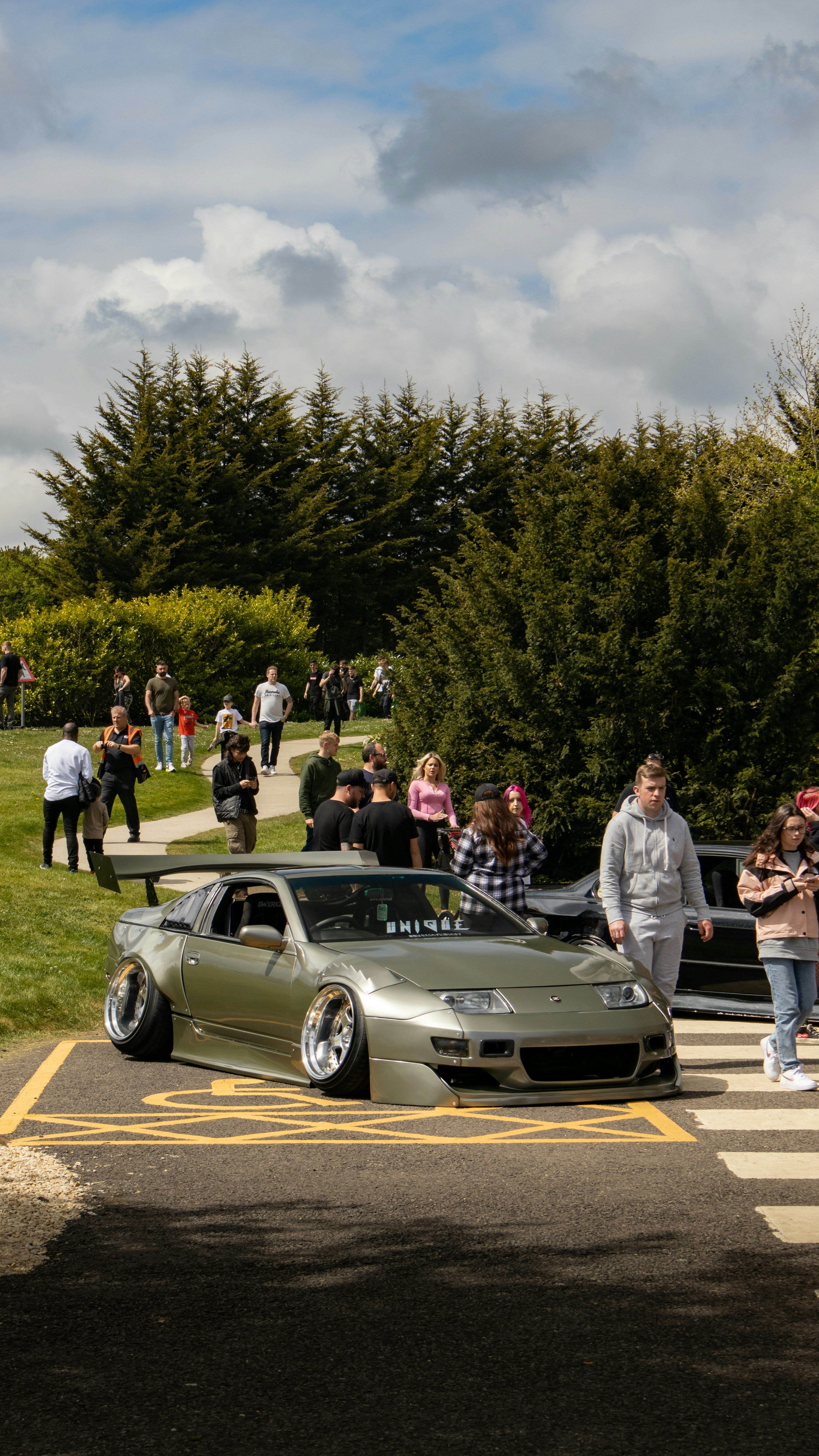 A group of people standing around a car in a parking lot photo – Free ...