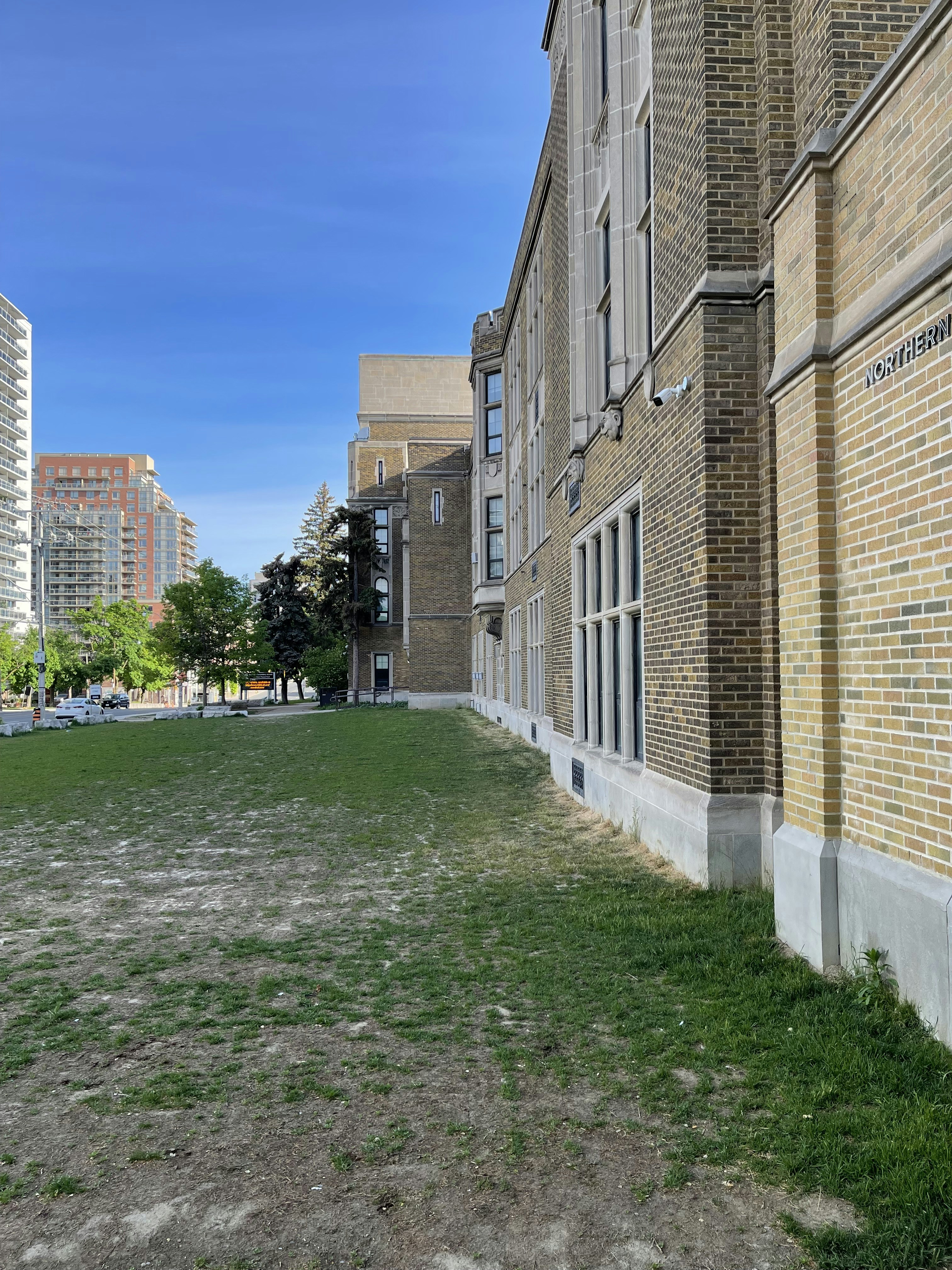 A grassy area in front of a brick building photo – Free Blue Image on ...