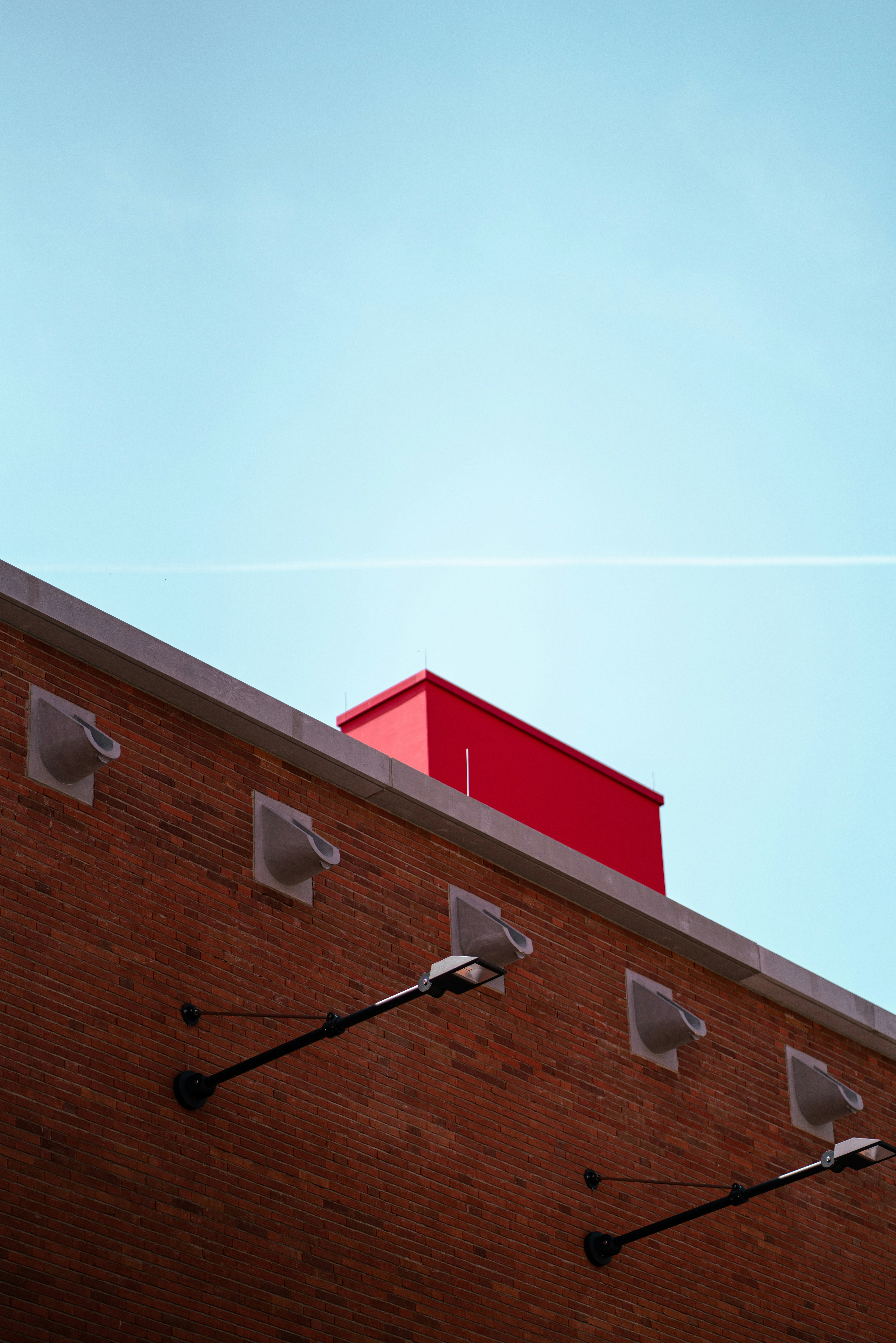 Crimson Rooftop Box Crowns a Brick Facade Under a Cerulean Sky
