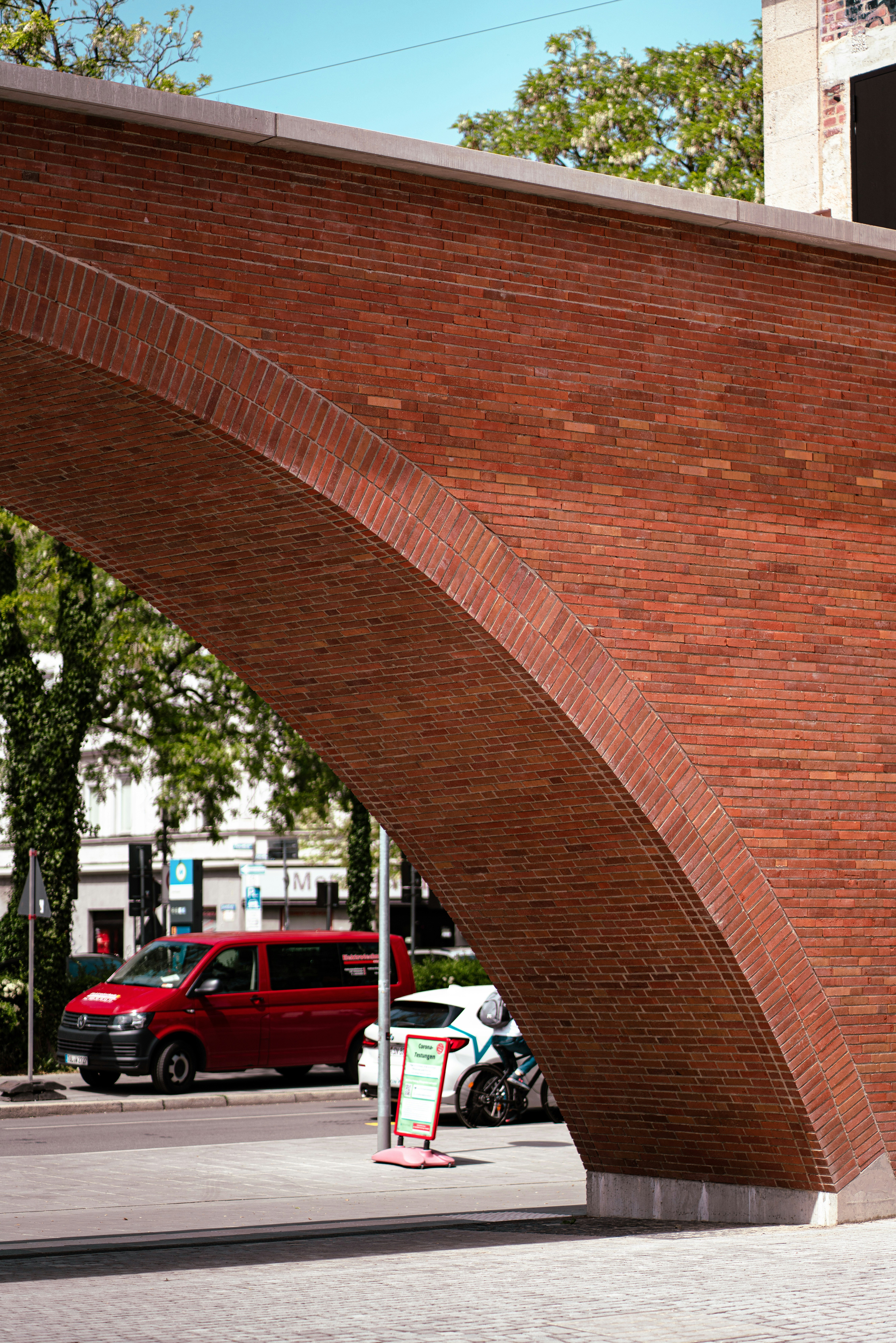 A striking brick archway framed by lush greenery and urban elements, highlighting the blend of nature and architecture.