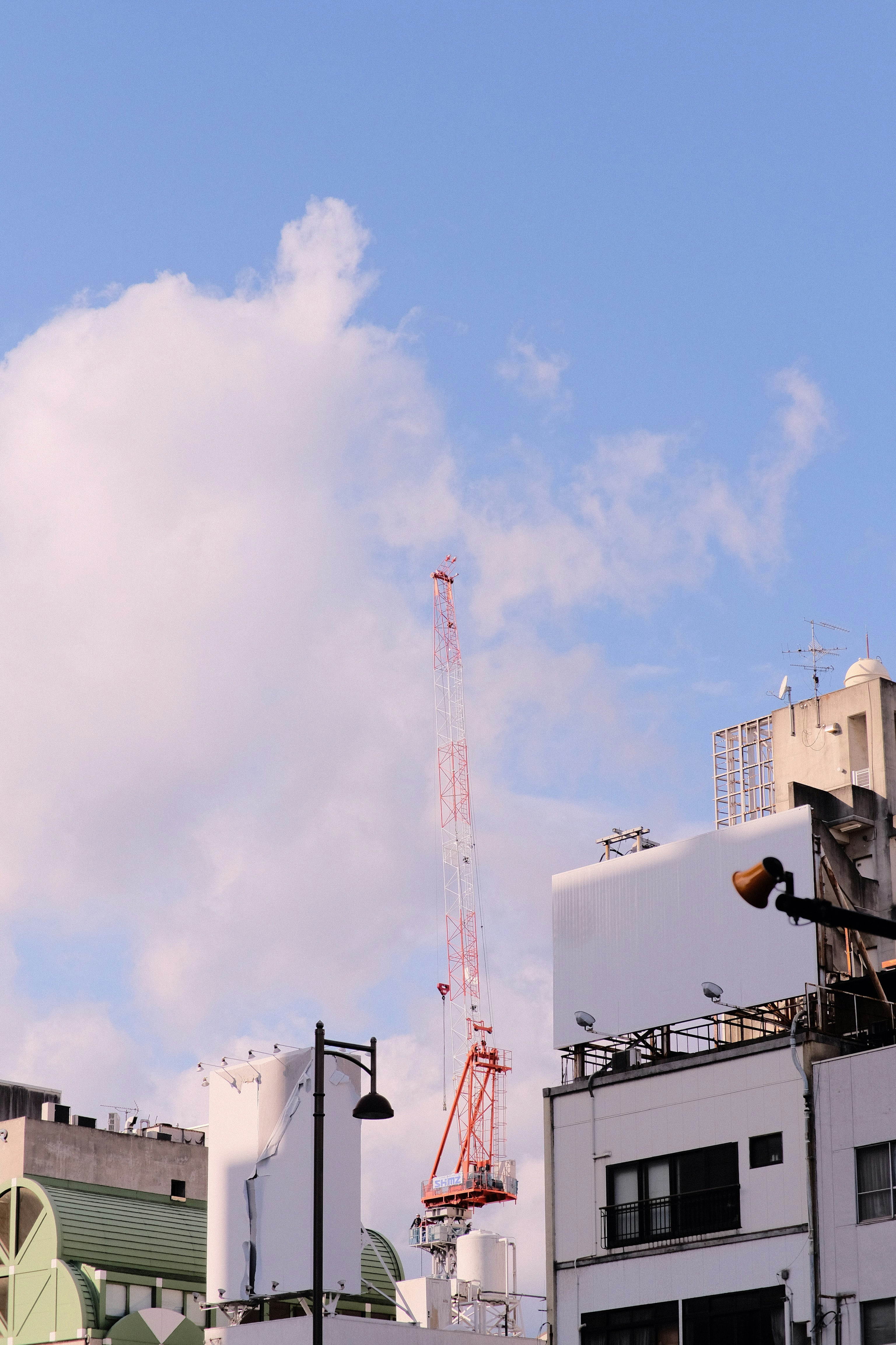 A crane on top of a building next to a traffic light photo – Free Blue ...