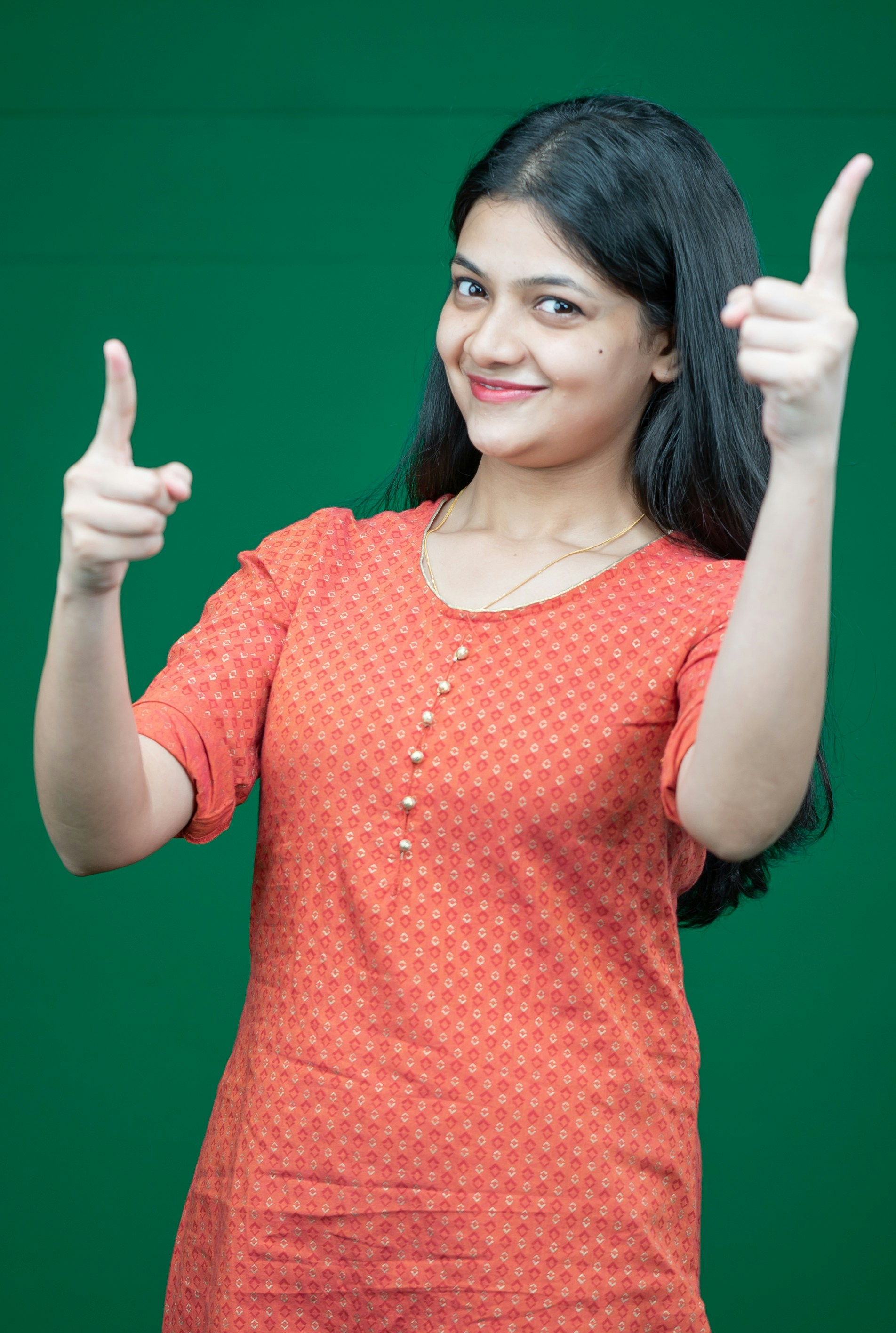 Une femme faisant un signe du pouce levé devant un fond vert photo ...
