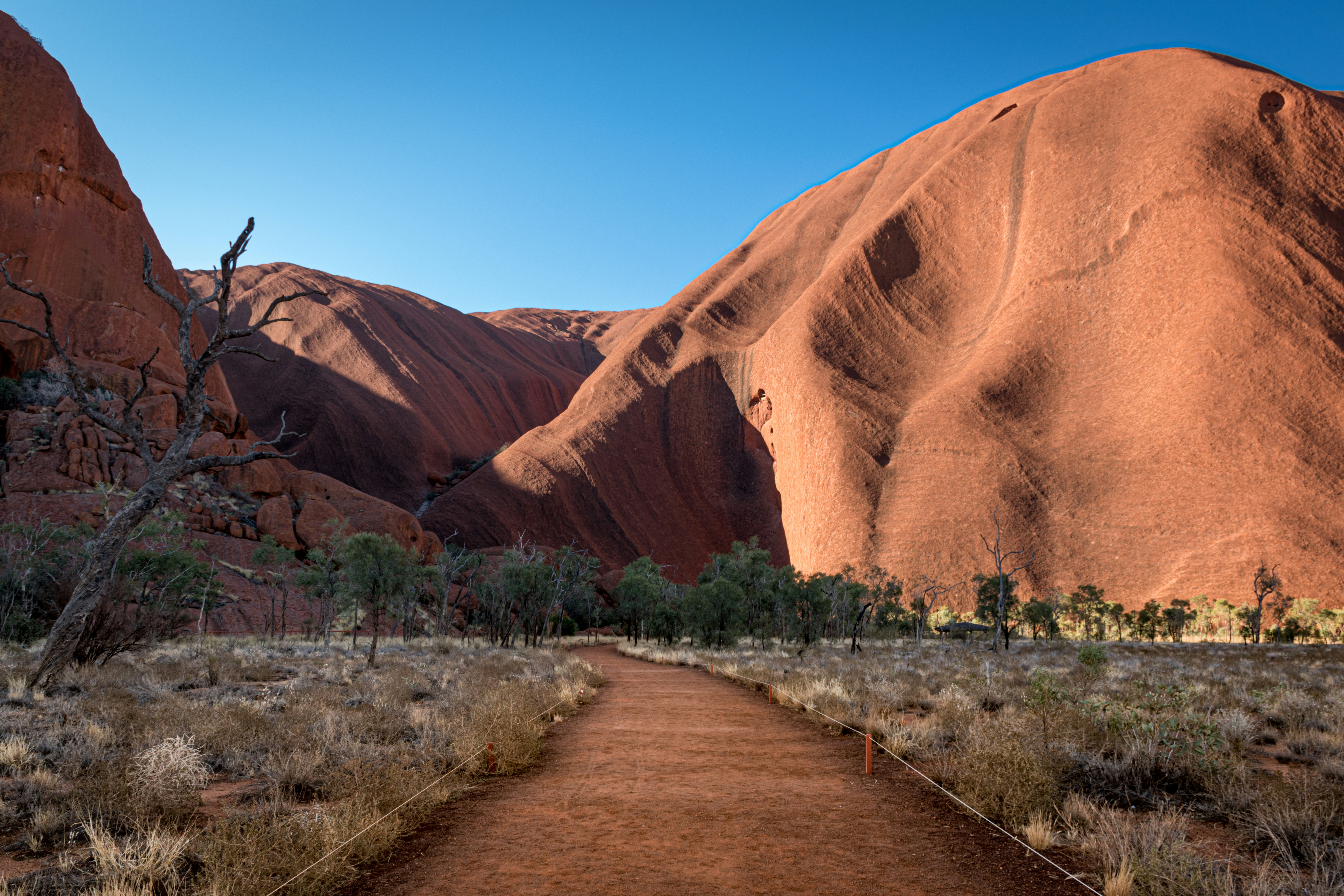 Trail through a desert corridor toward a colossal crimson rock dome