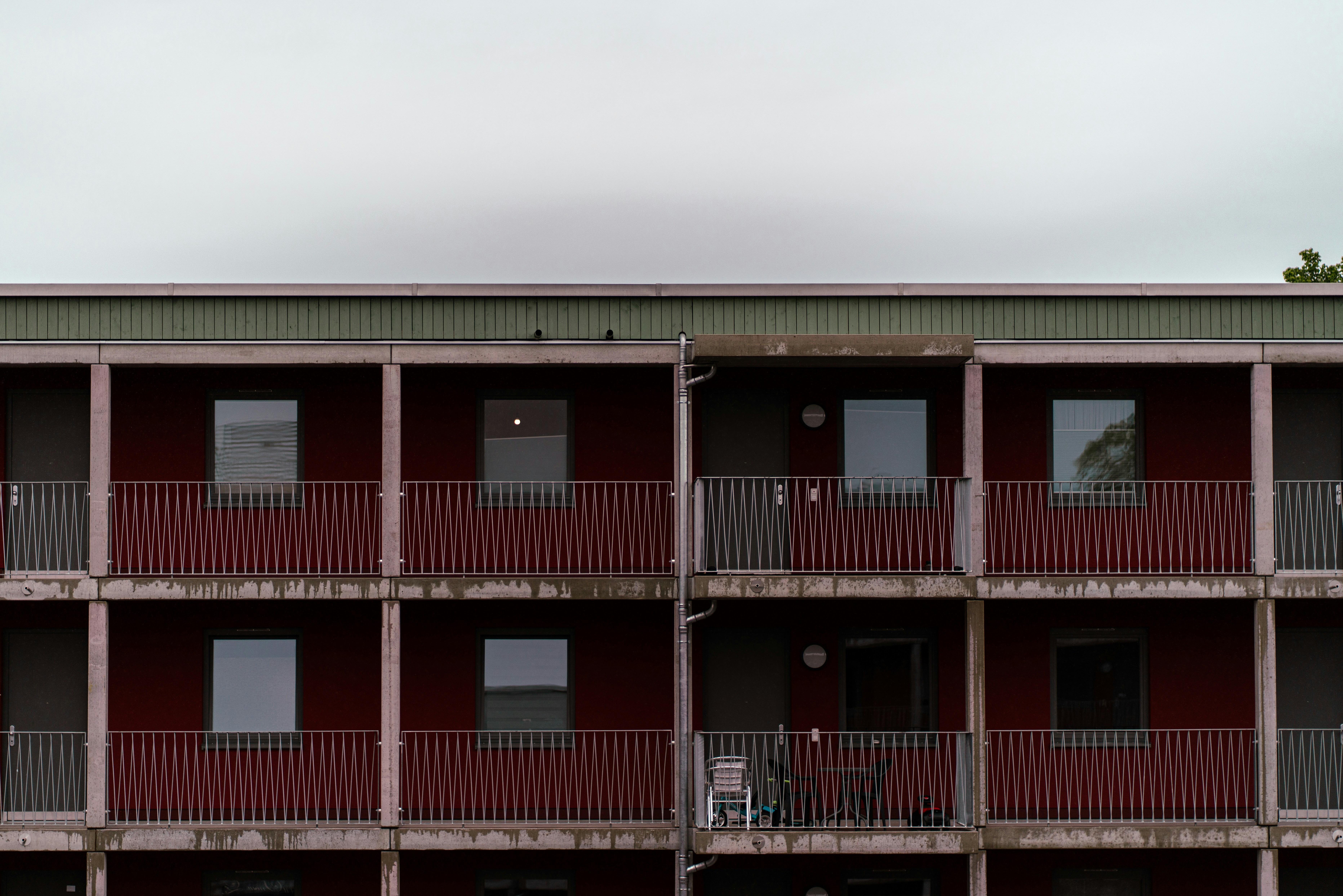 A weathered multi-story building with red walls and balconies, showcasing a blend of urban decay and architectural lines.
