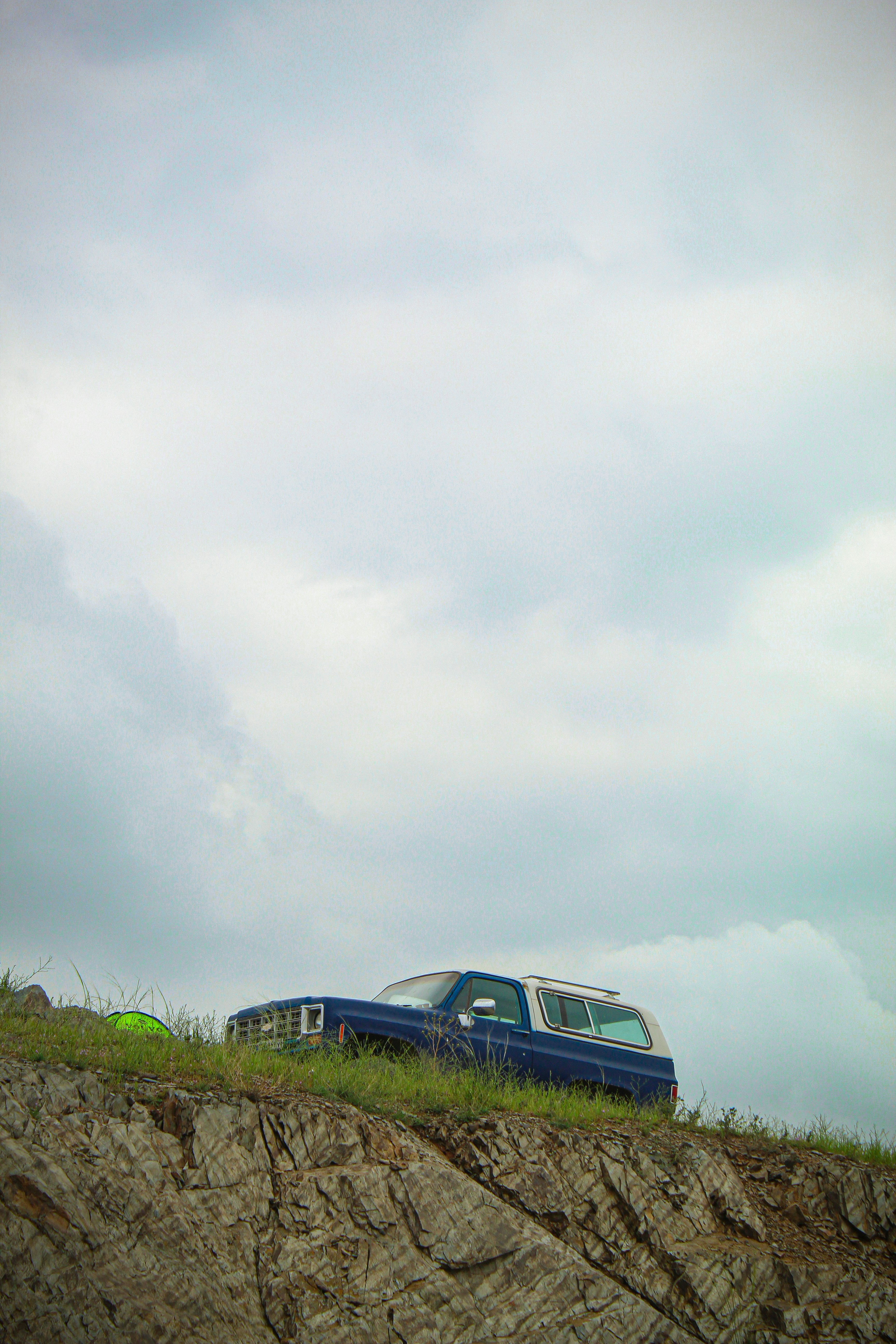 Blue Wagon on a Cliff: A Quiet Ride Beneath Stormy Skies