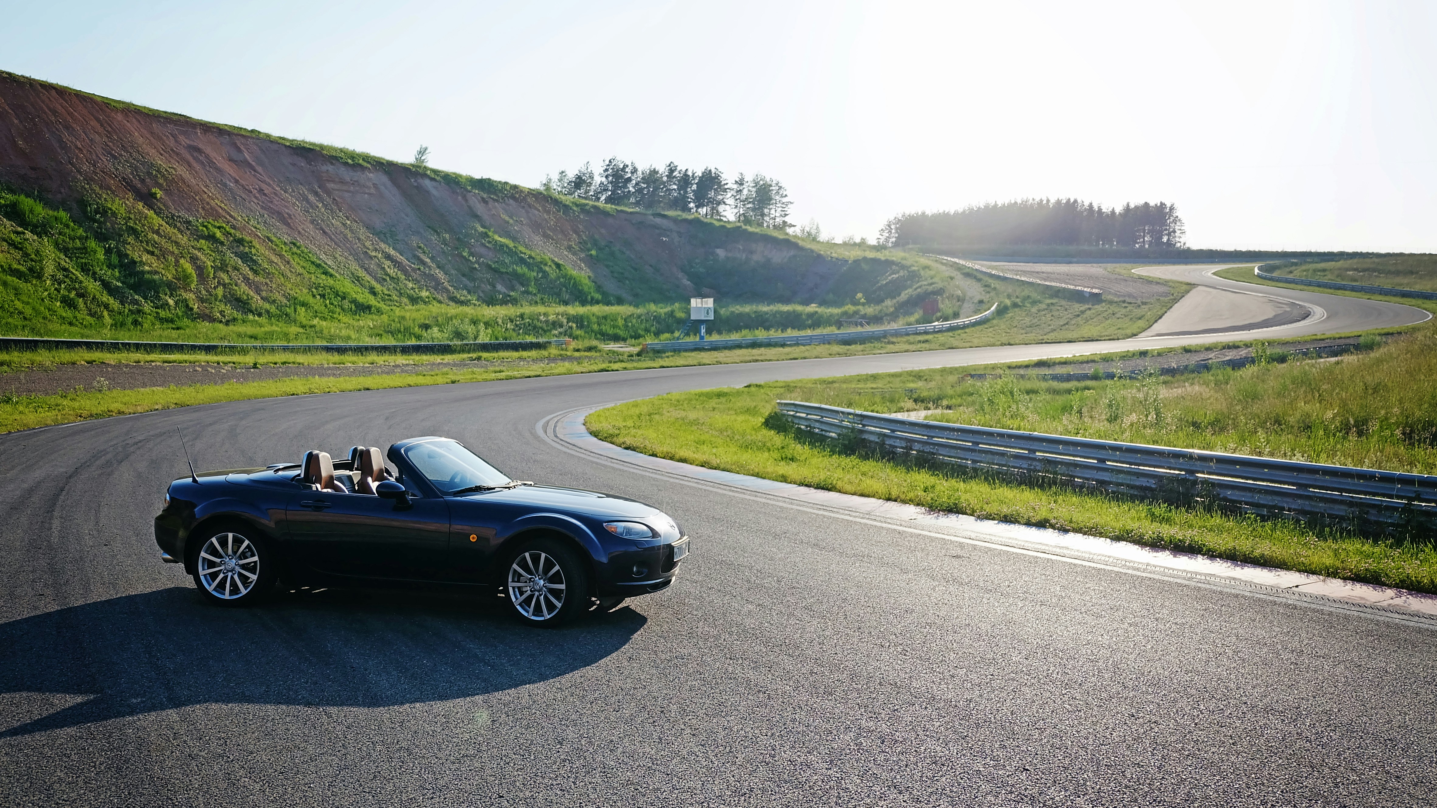 A black sports car driving down a curvy road photo – Free Road Image on ...