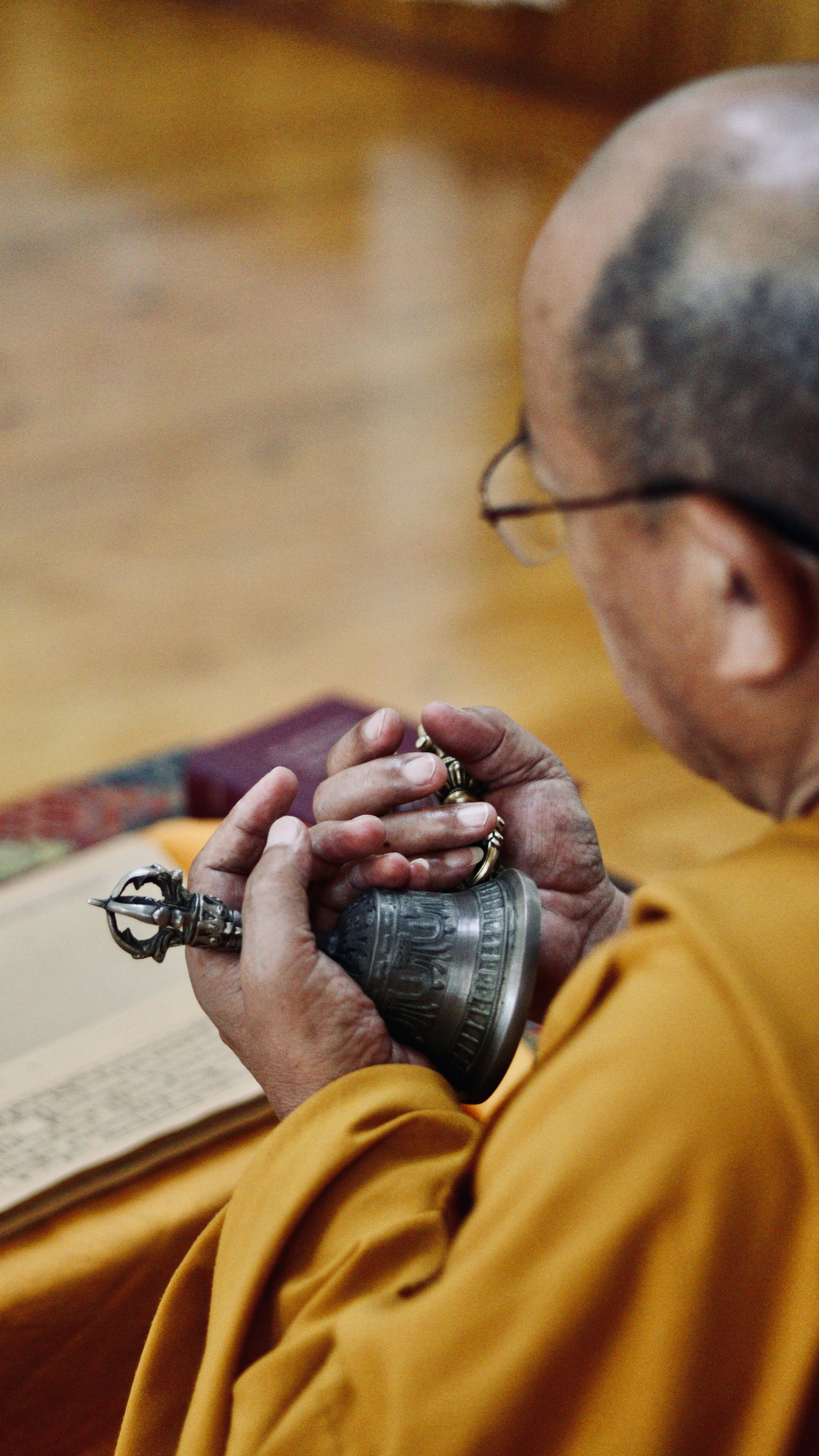 Hands and prayer bell: meditation in orange robes