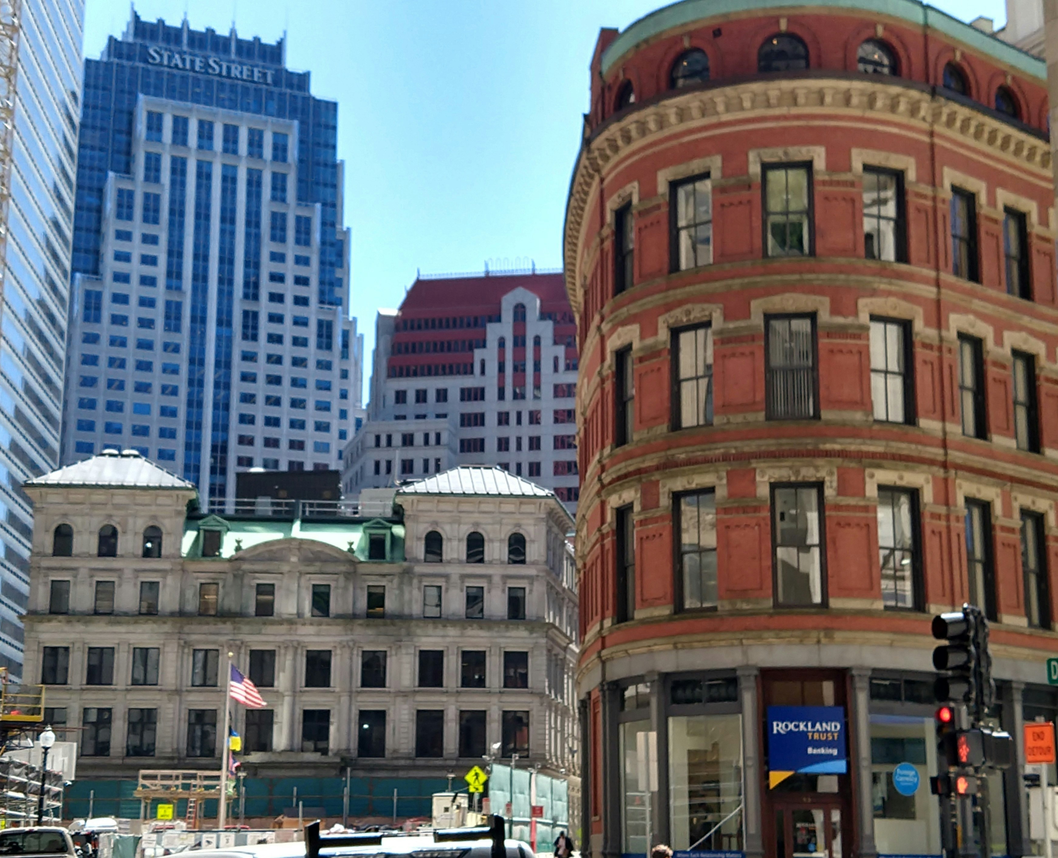 Historic brick building contrasts with modern skyscrapers in a bustling cityscape. The scene captures the dynamic blend of past and present architecture.