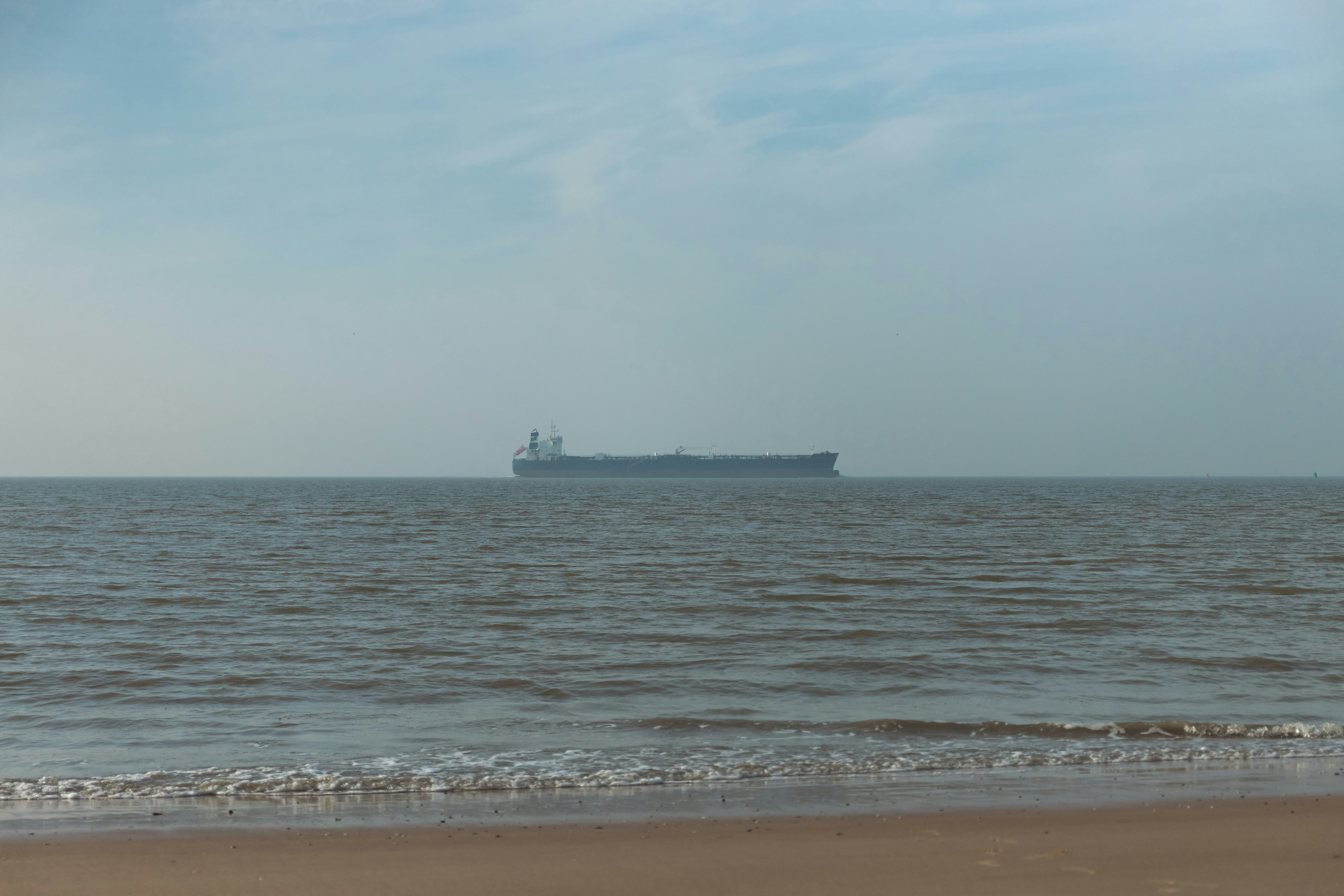 A large cargo ship in the distance on the ocean photo – Free Grey Image ...