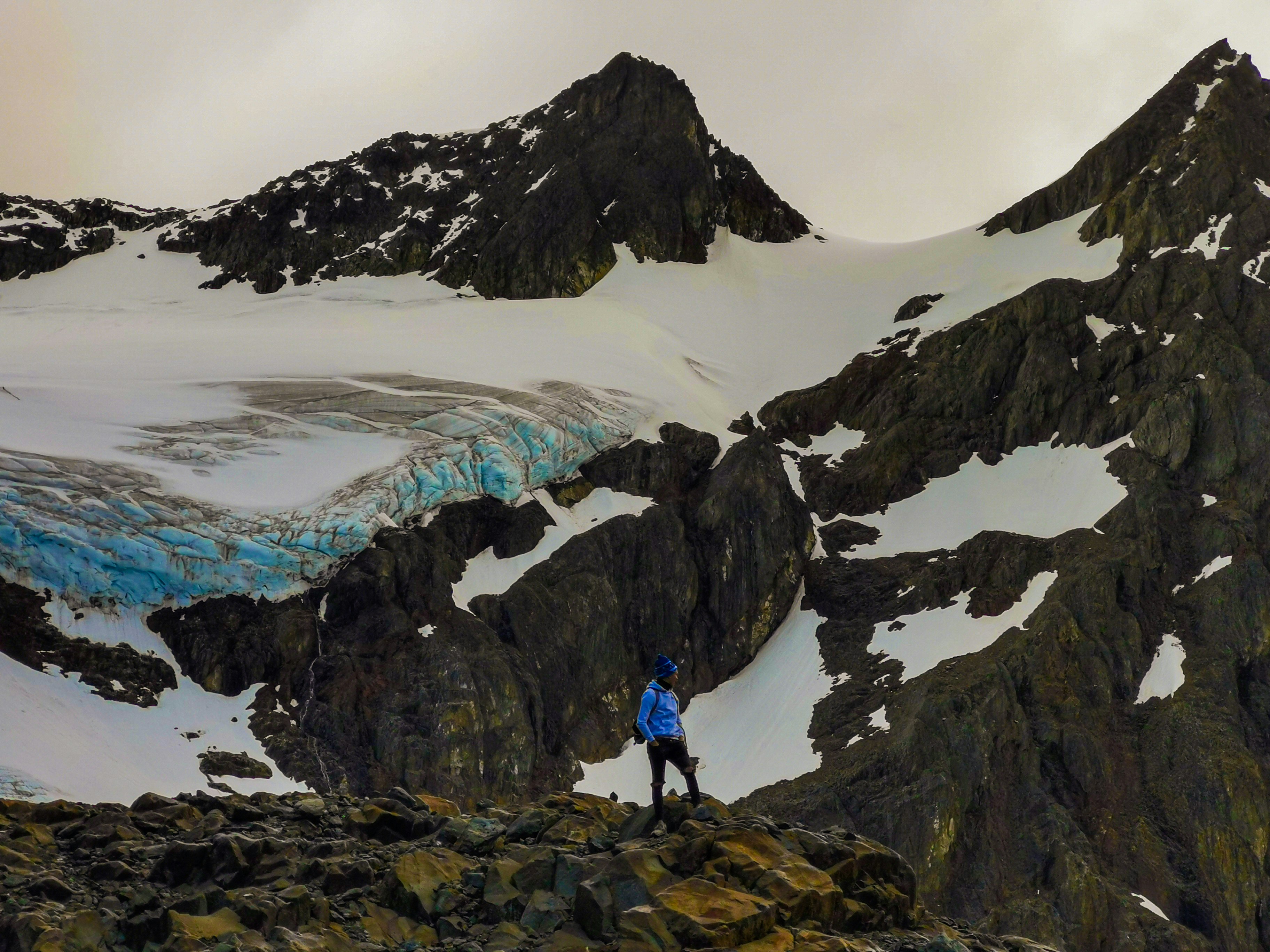 Lone Climber on a Serrated Ledge Beneath a Blue Glacier