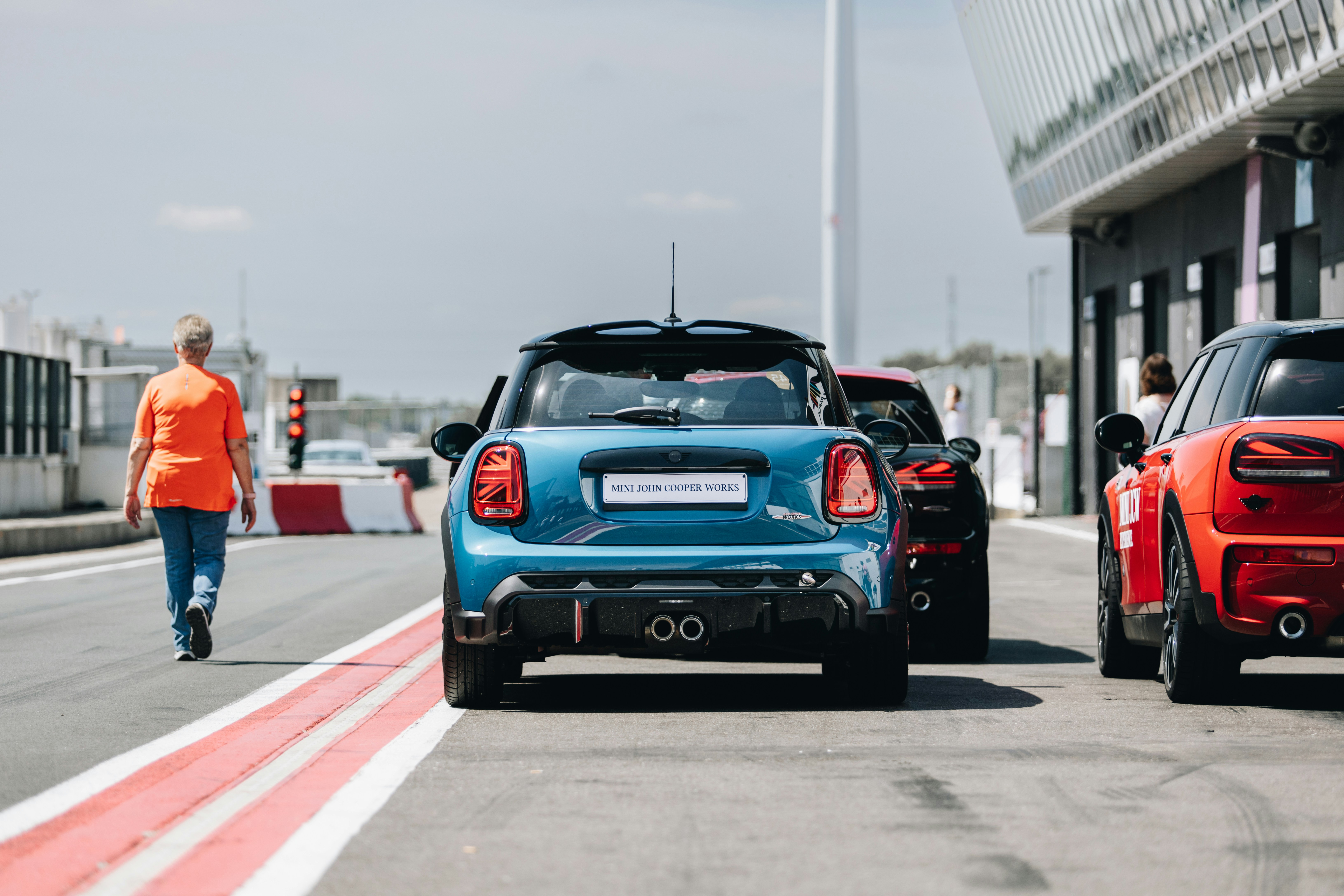 A man walking next to two cars on a race track photo – Free Person ...