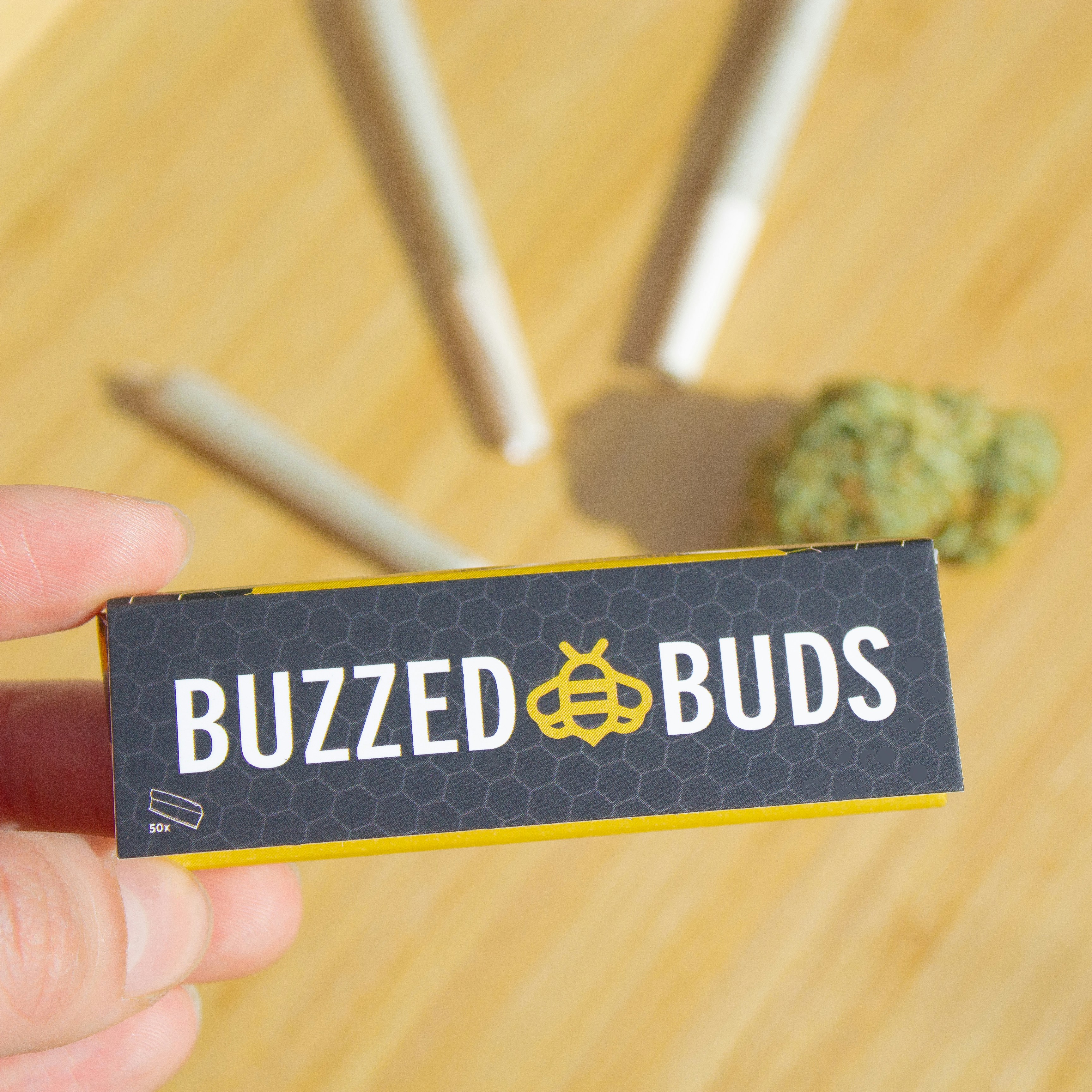 A person holding up a business card with the word buzzed buds on it ...