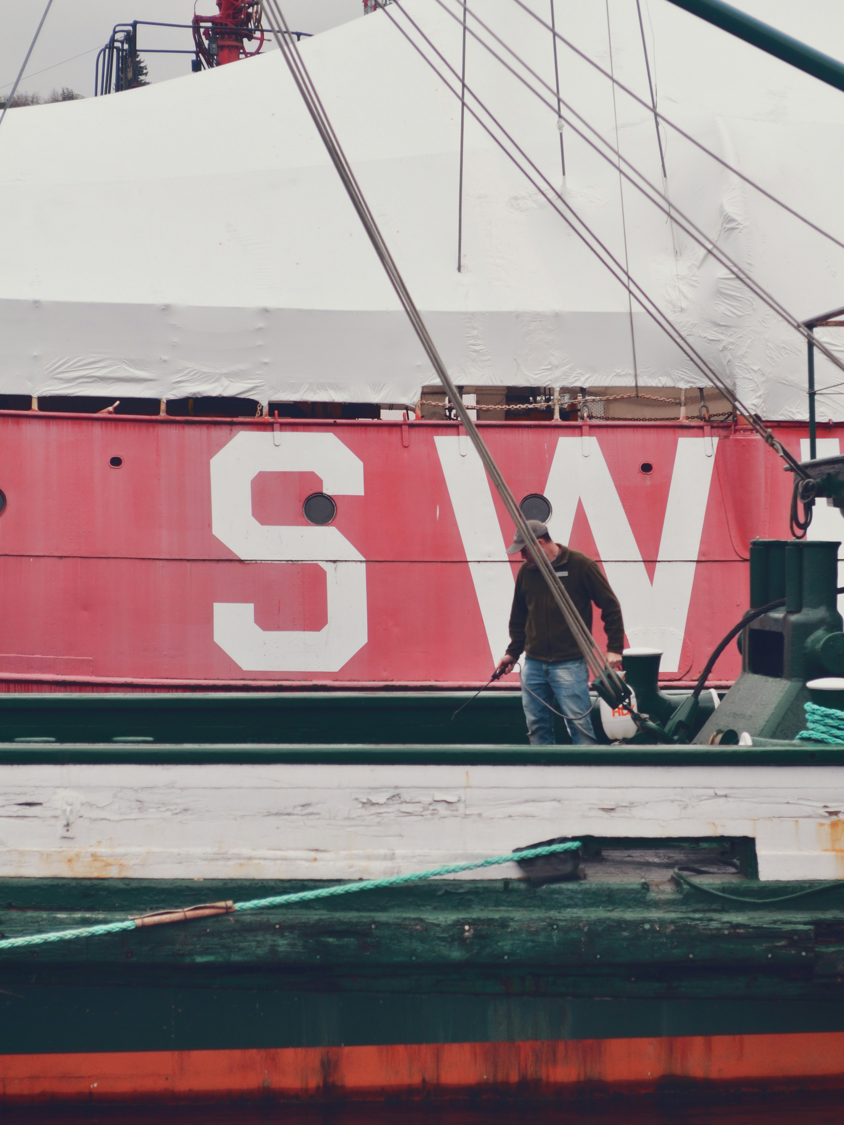 Crewman Beneath a Web of Rigging Against a Bold Red Hull