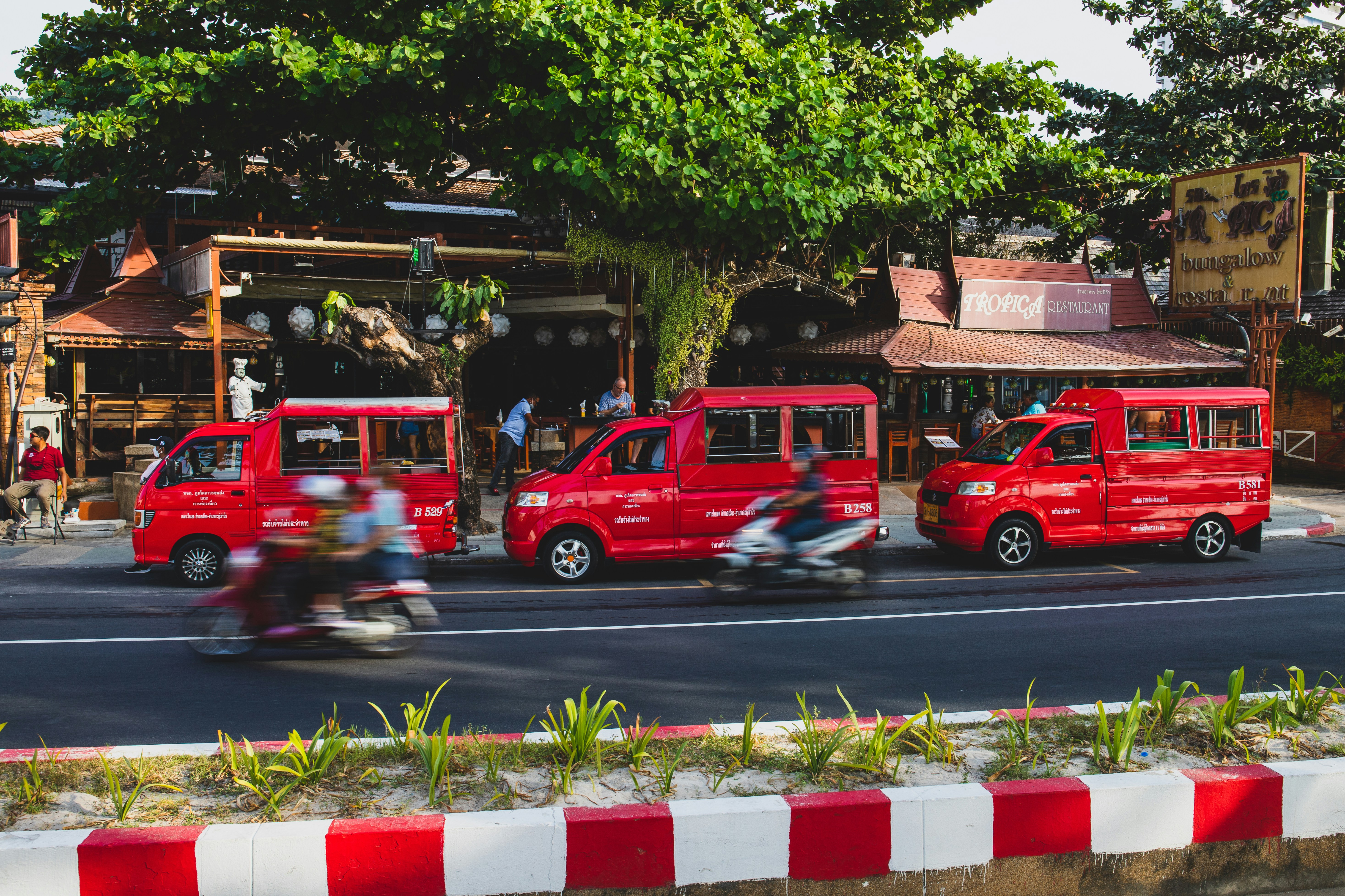 A group of red buses driving down a street photo – Free Road Image on ...