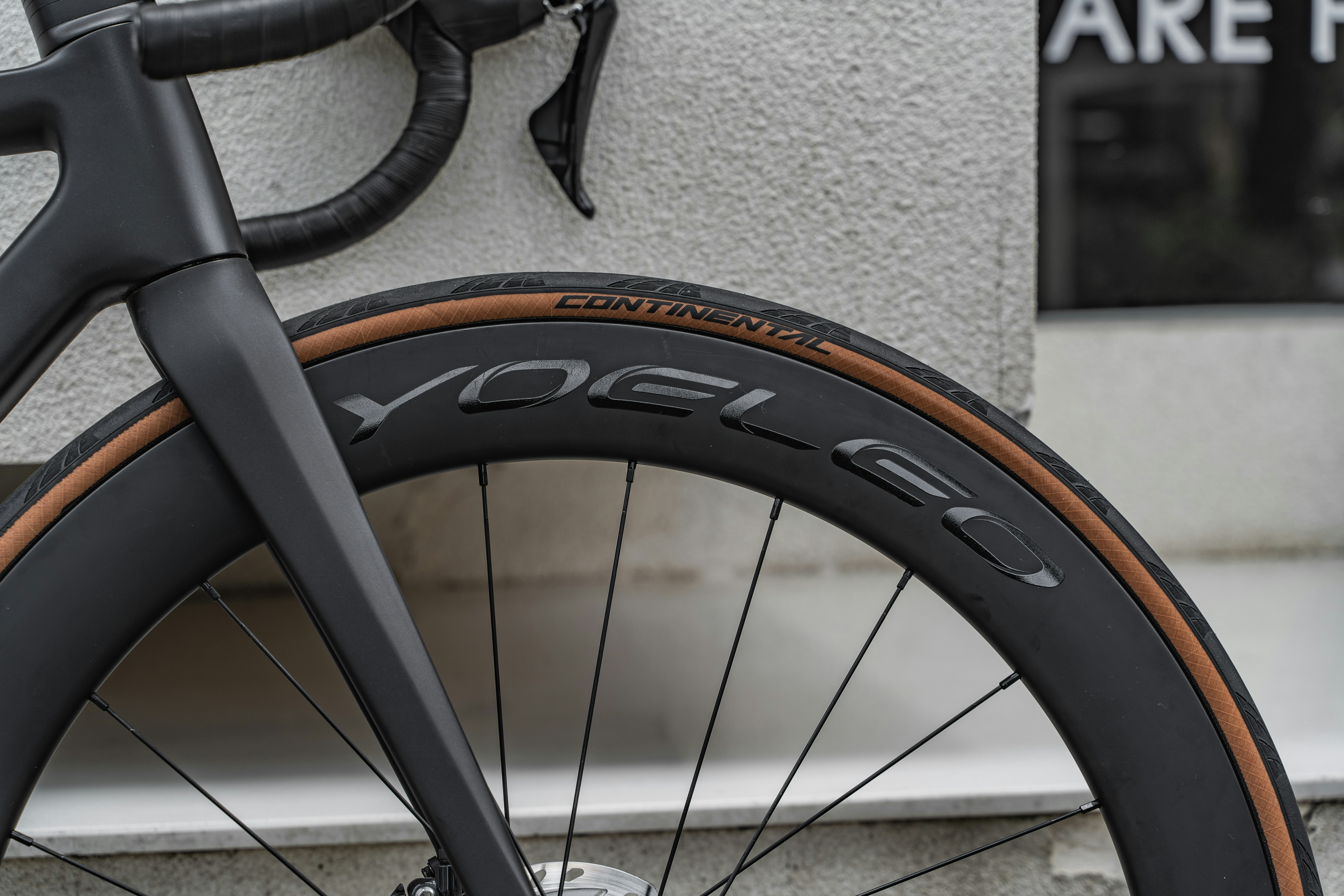 Close-up of a sleek bicycle wheel with a high-performance tire against a textured wall.