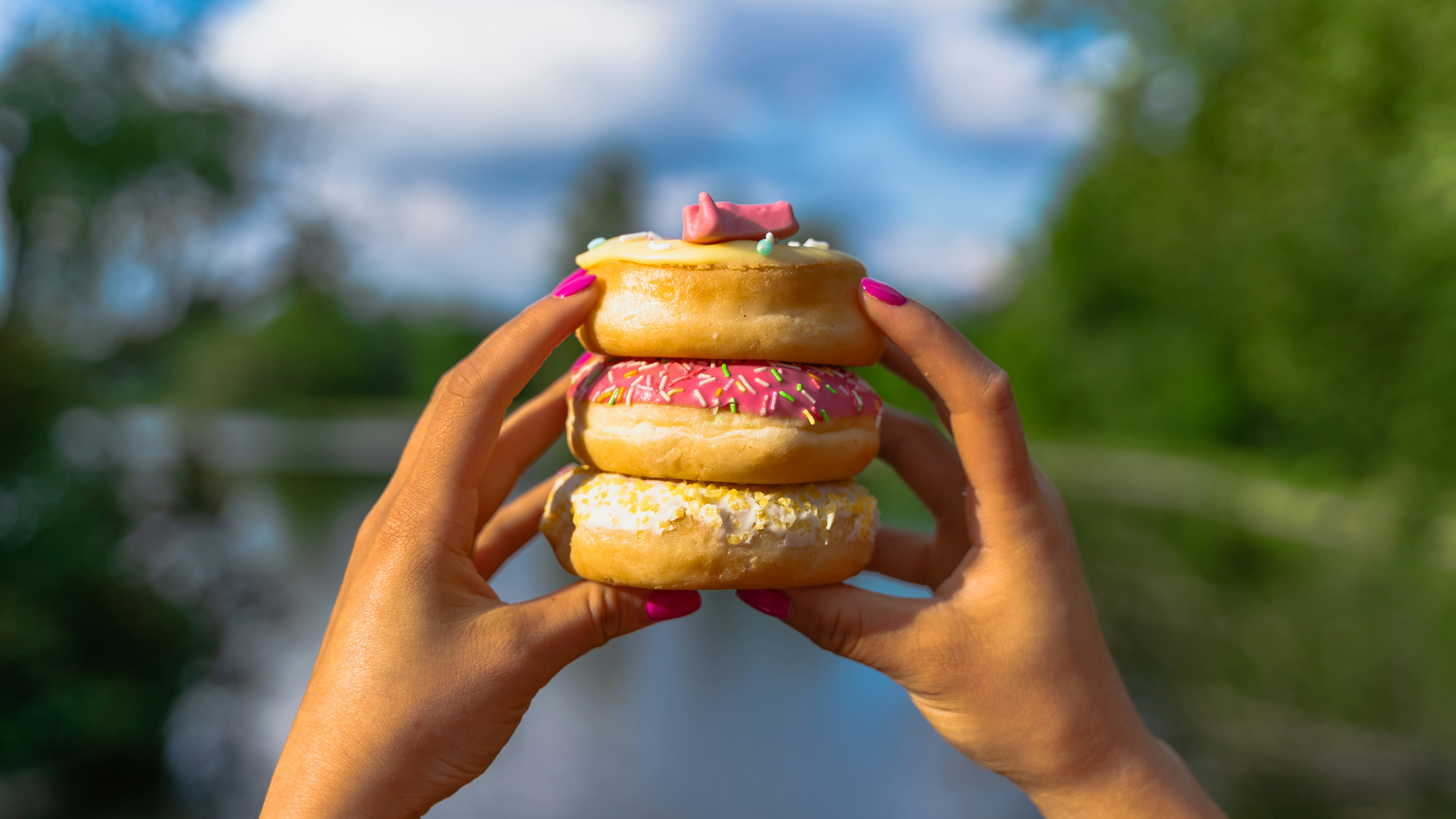 A woman holding a stack of donuts in front of her face photo – Free ...