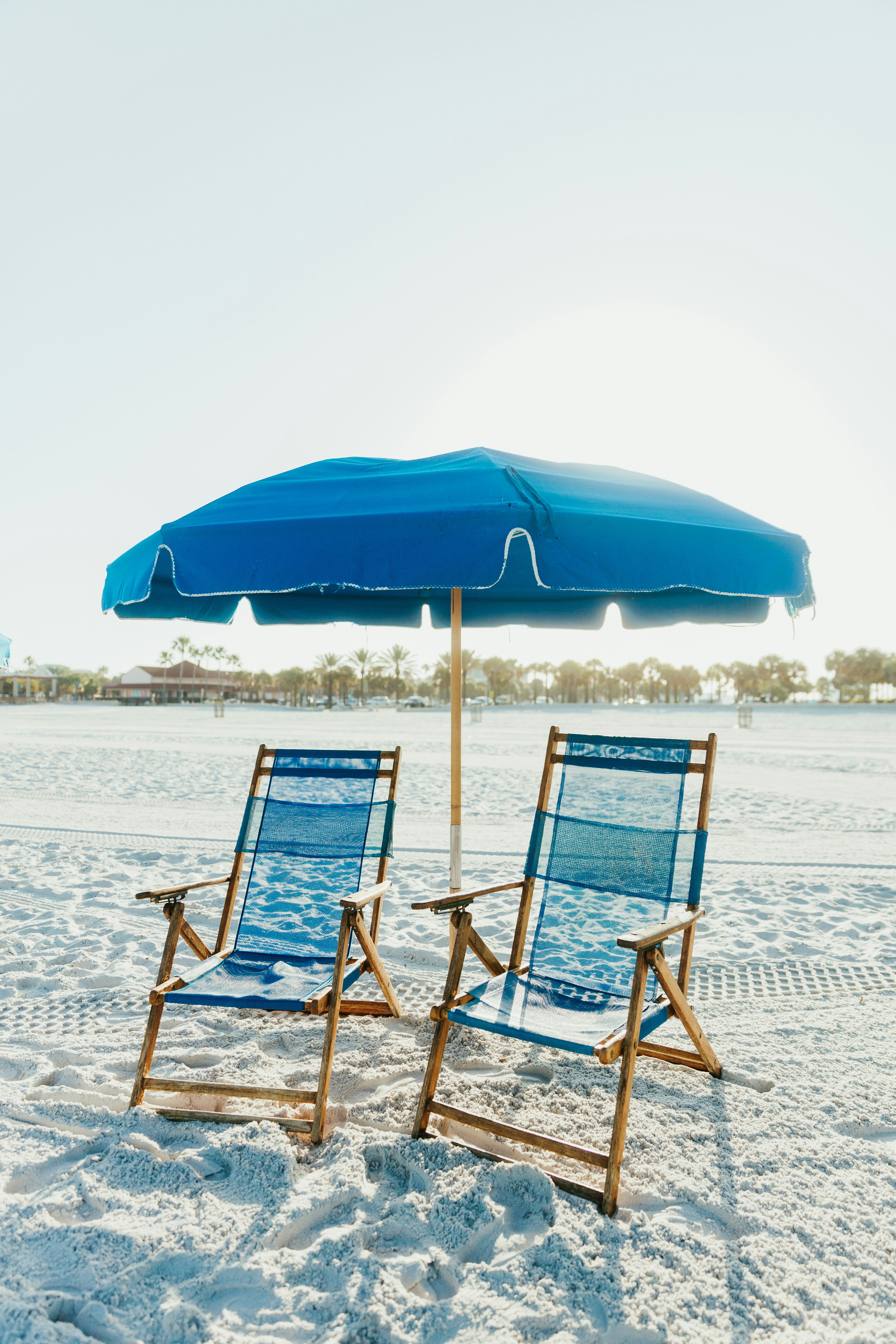 Two Cerulean Beach Chairs Beneath a Broad Umbrella on Quiet White Sand
