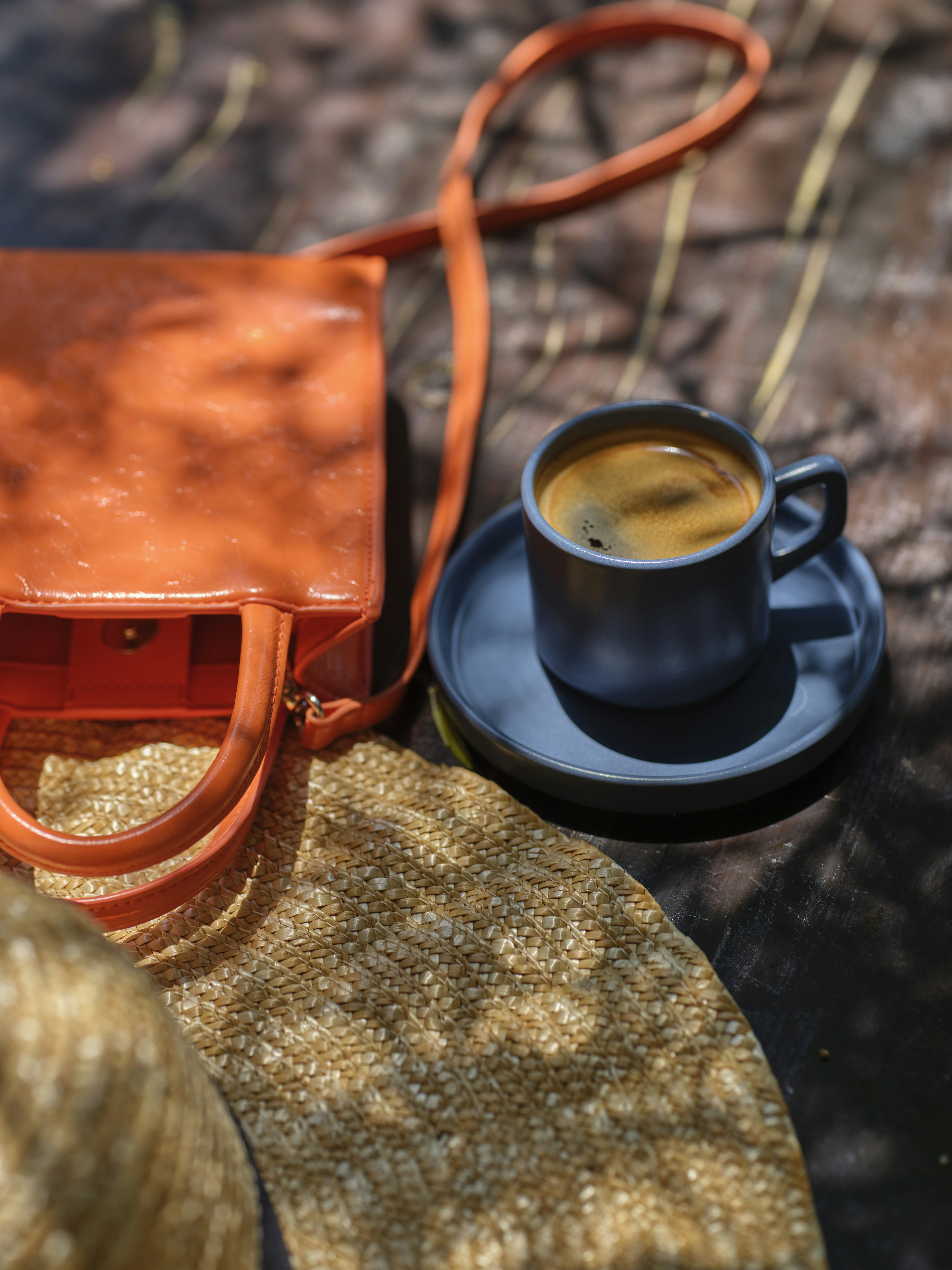 Straw hat, orange bag and delicious coffee on the wooden table