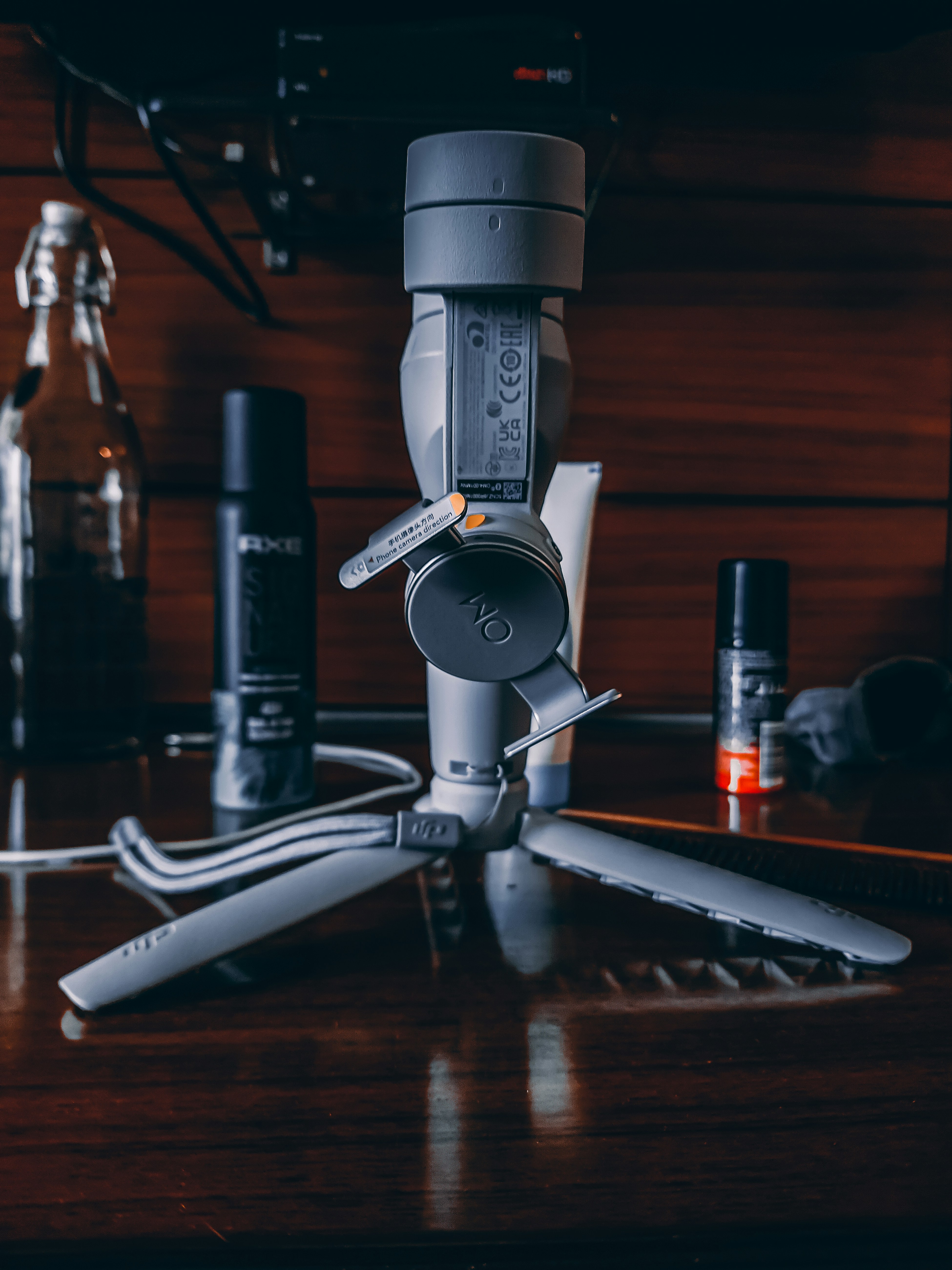 A sleek, modern tripod stands prominently on a polished wooden surface, surrounded by various grooming products. The design emphasizes functionality and style.
