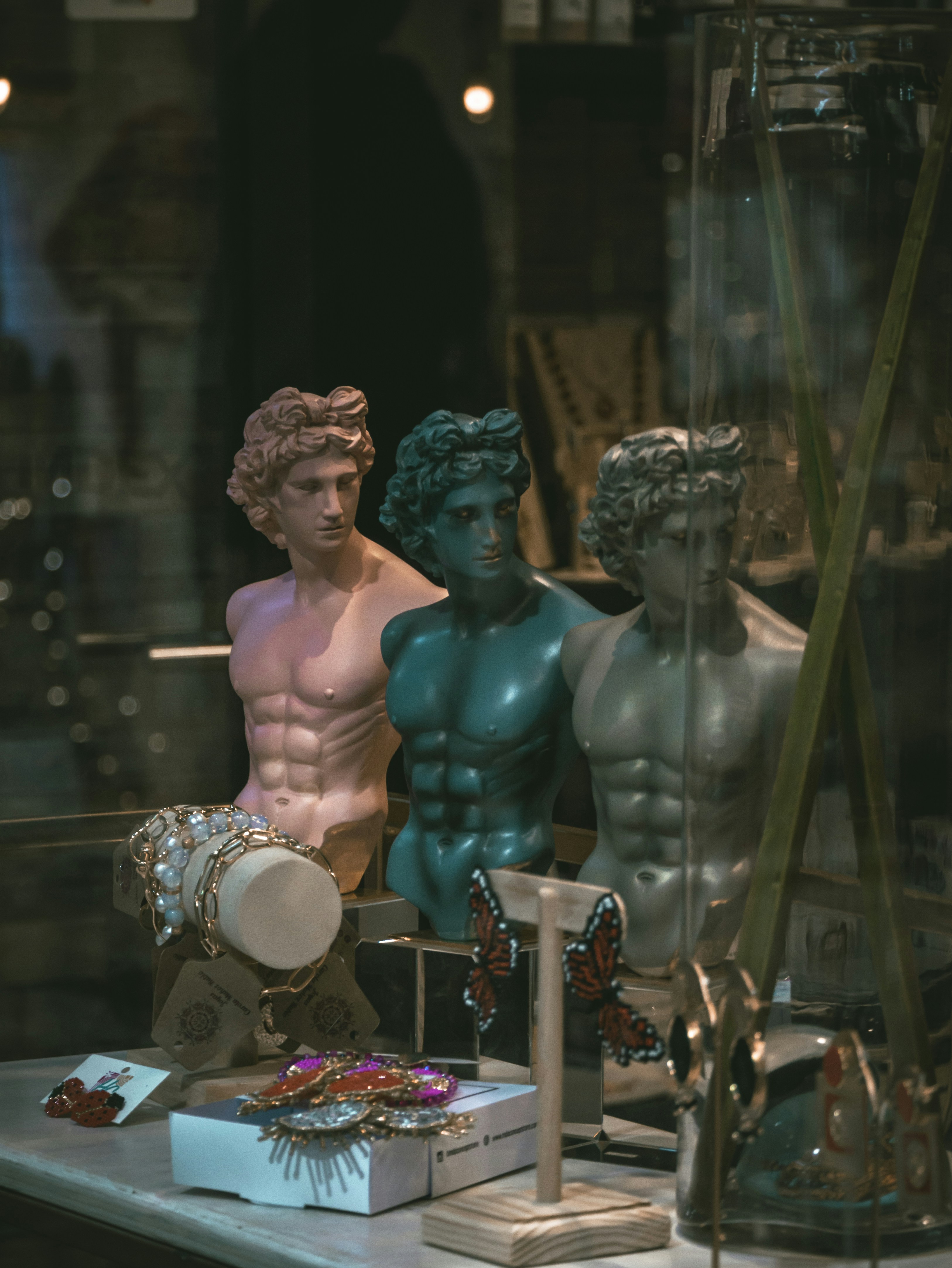 Three Classical Busts Guard a Display of Trinkets in a Curio Shop
