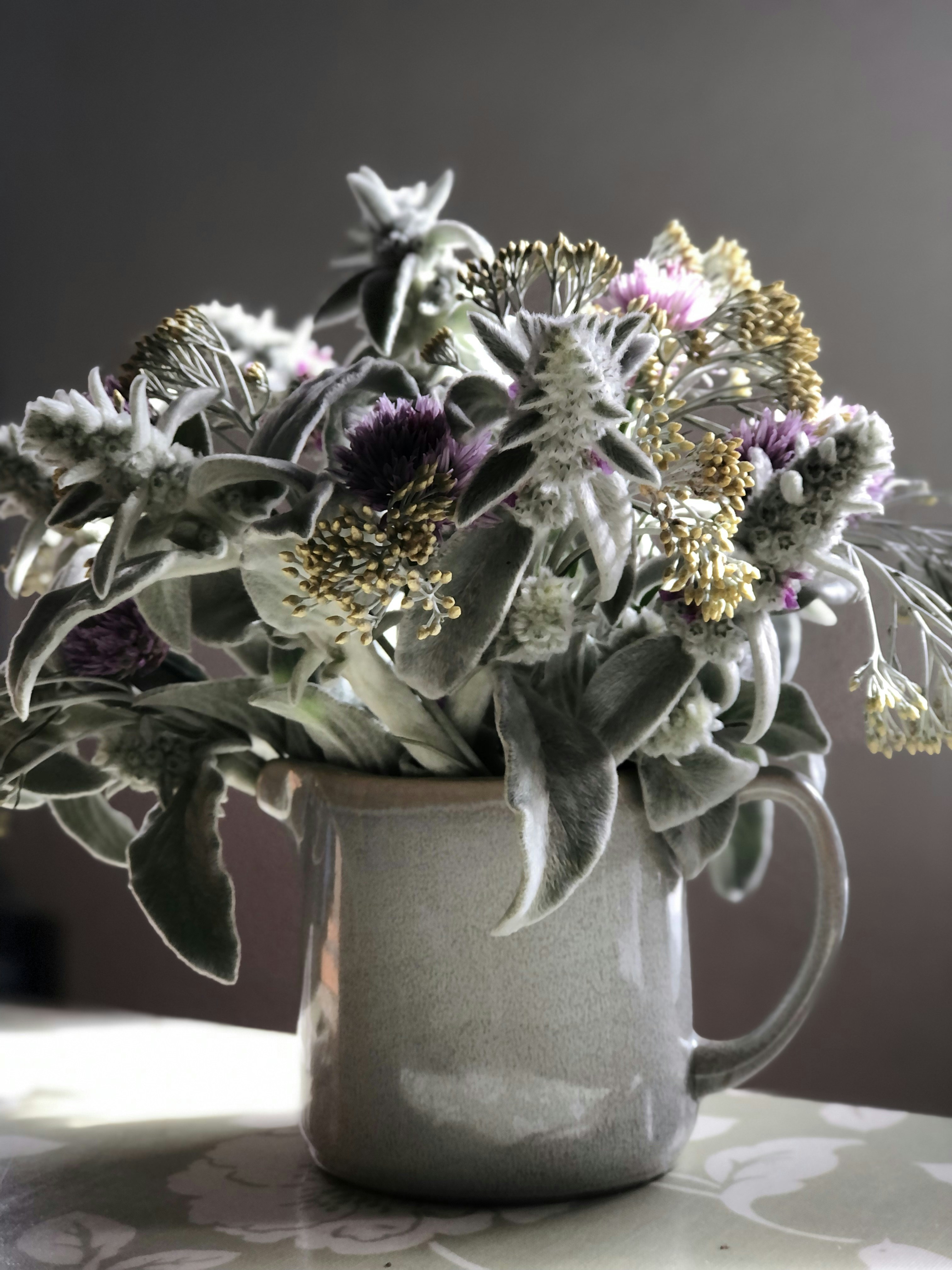 A charming bouquet of textured flowers in a soft gray ceramic mug, capturing the essence of nature's beauty indoors.