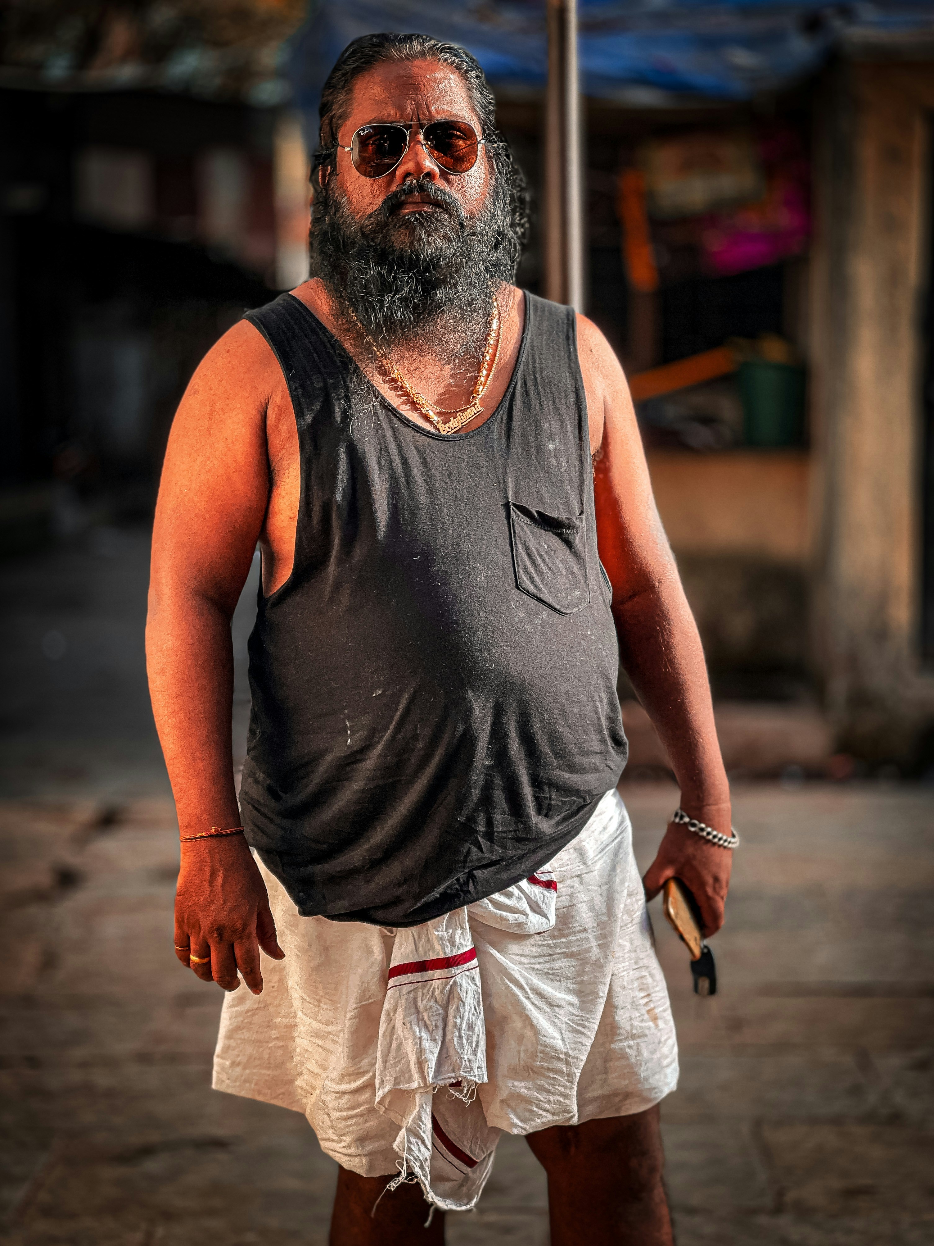 The Sunlit Standpoint: A Bearded Man in Sunglasses Under Urban Shade
