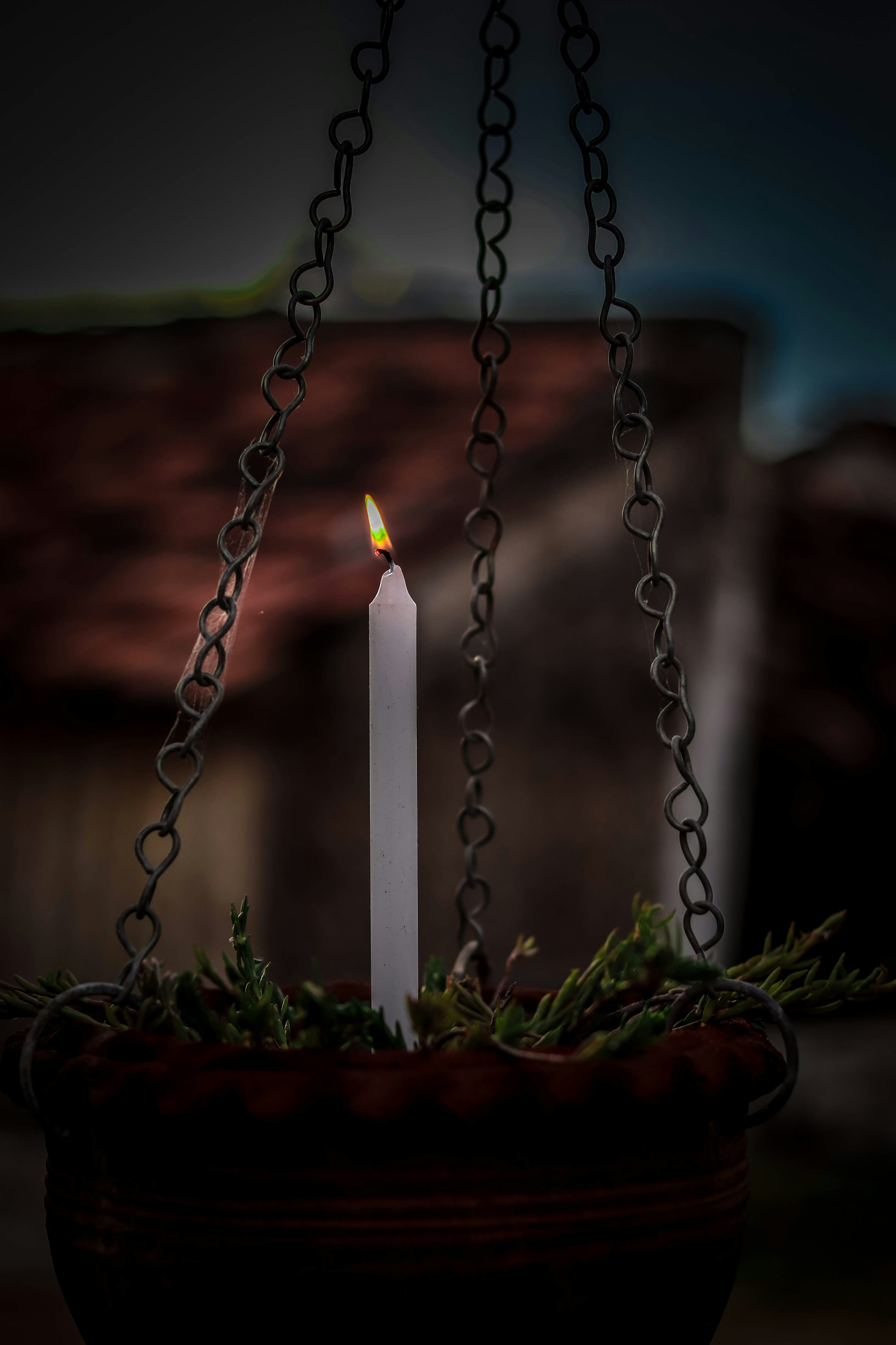 Lone Flame Between Chains: Candle in a Hanging Pot