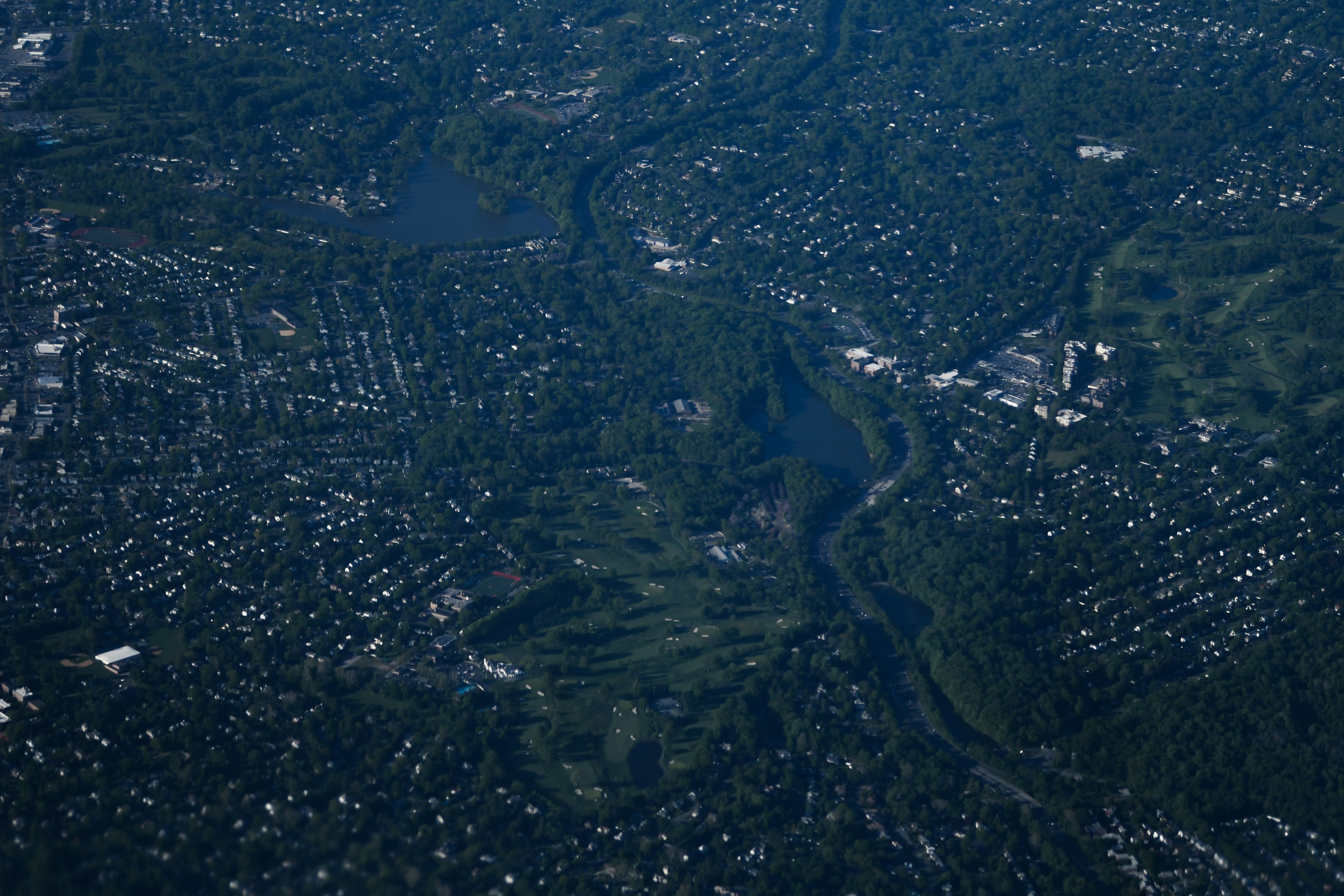 Aerial view showcasing the blend of lush greenery and urban infrastructure, with rivers meandering through the landscape. The scene highlights the coexistence of nature and city life.